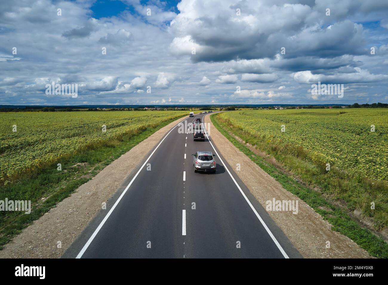 Aerial view of intercity road between green agricultural fields with ...