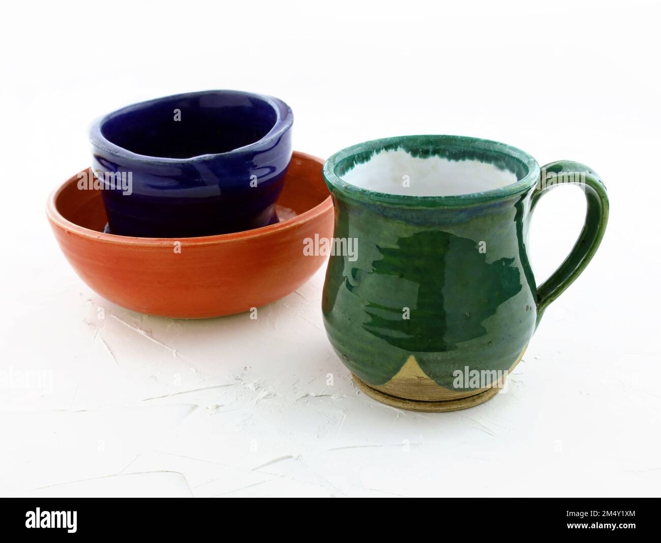 Color ceramic dishes on a white background. Cup made of green clay ...