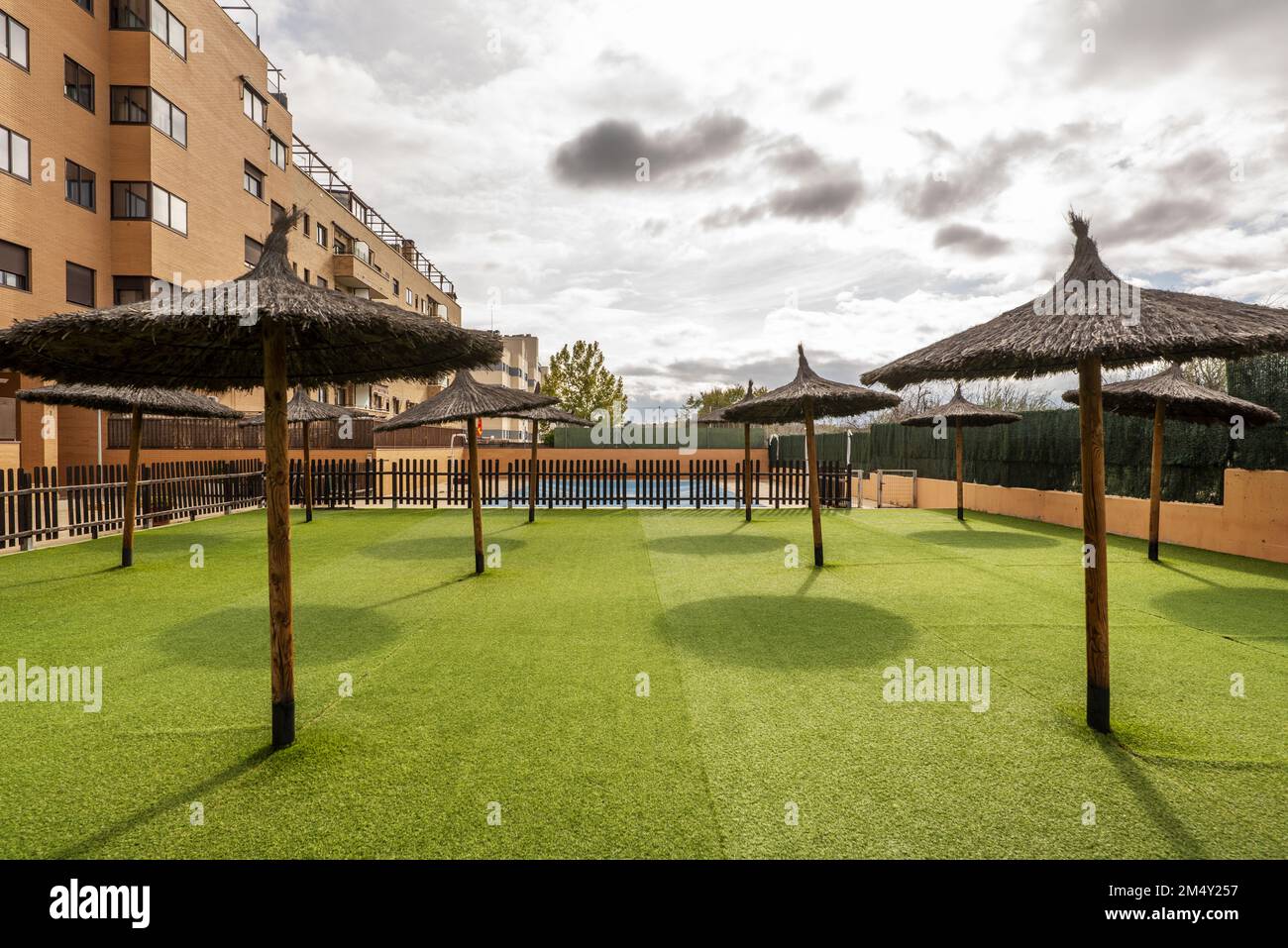 A communal patio with a swimming pool and fenced space with artificial ...