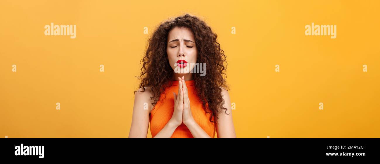 Nervous and concerned woman with curly hairstyle feeling hopeful ...