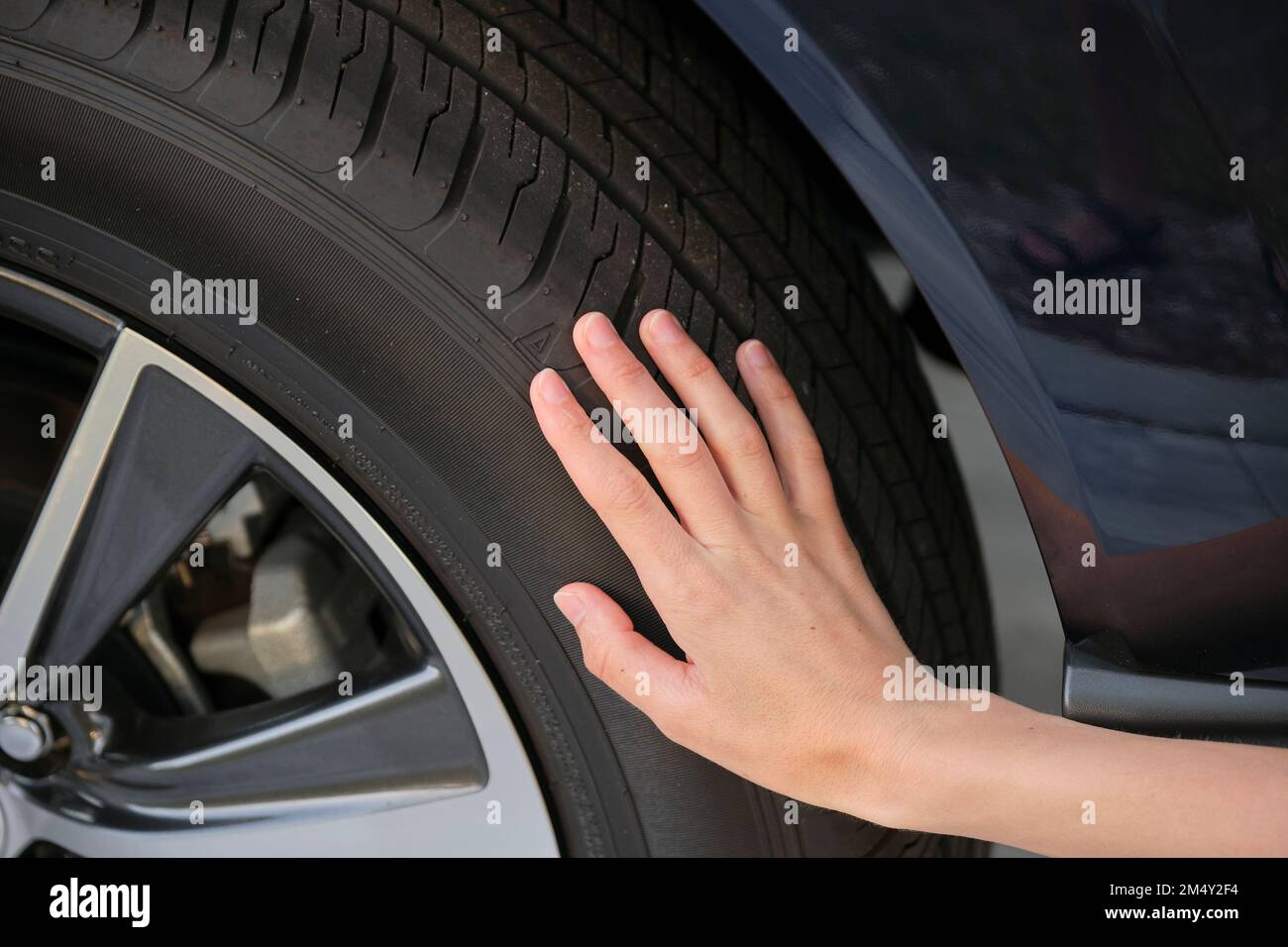 Female driver hands inspecting wheel tire of her new car. Vehicle ...