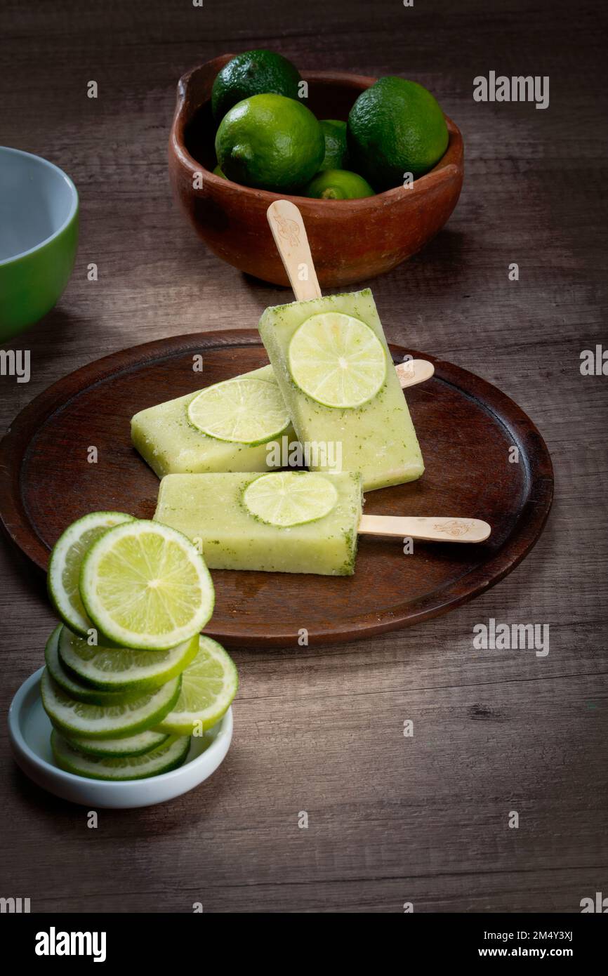 A vertical shot of lime flavor popsicles on a plate surrounded by full ...