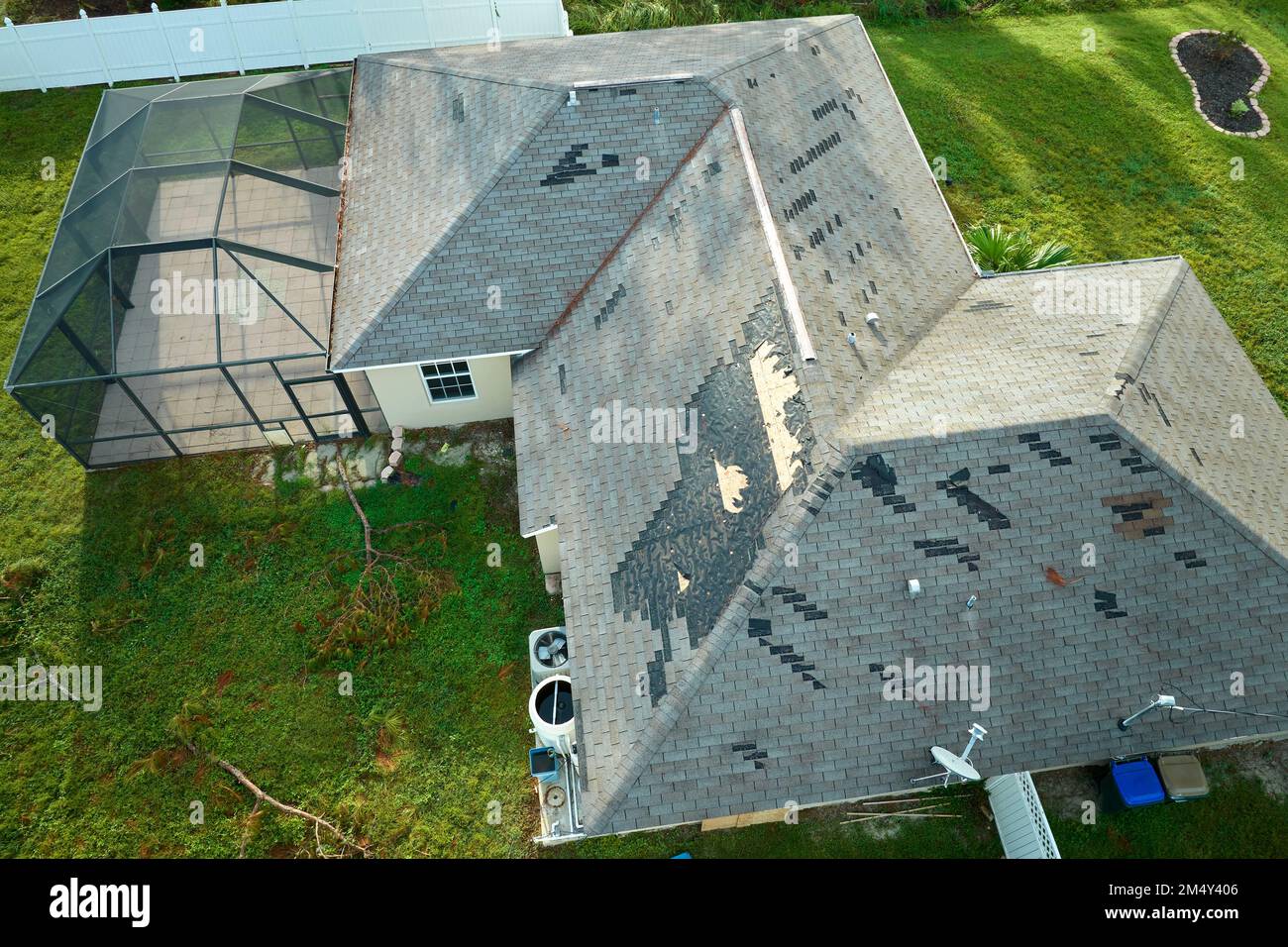Wind damaged house roof with missing asphalt shingles after hurricane ...