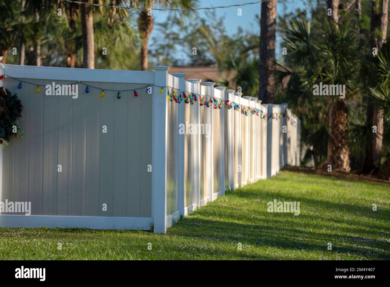White vinyl picket fence on green lawn surrounding property grounds for ...