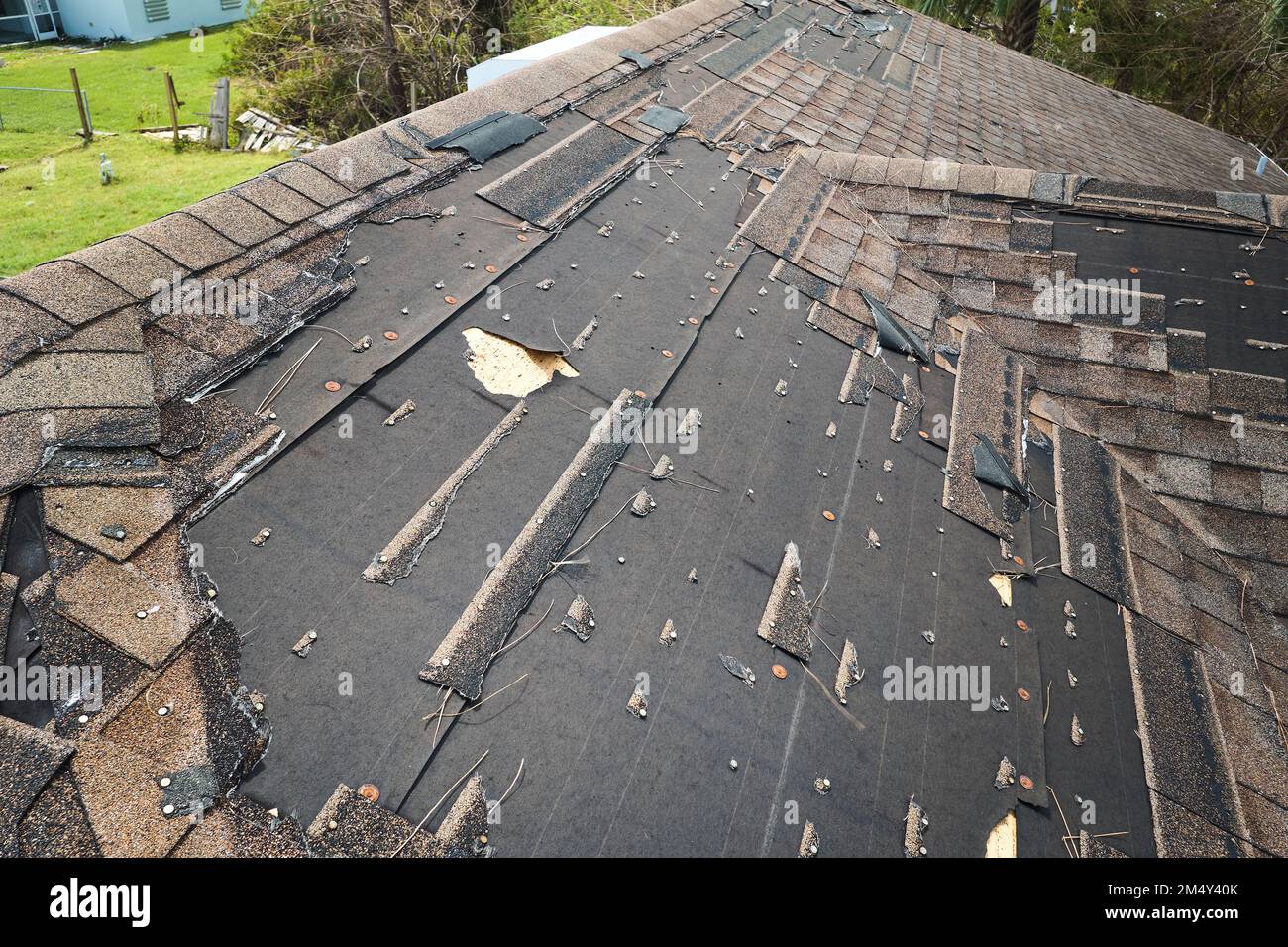 Wind damaged house roof with missing asphalt shingles after hurricane ...