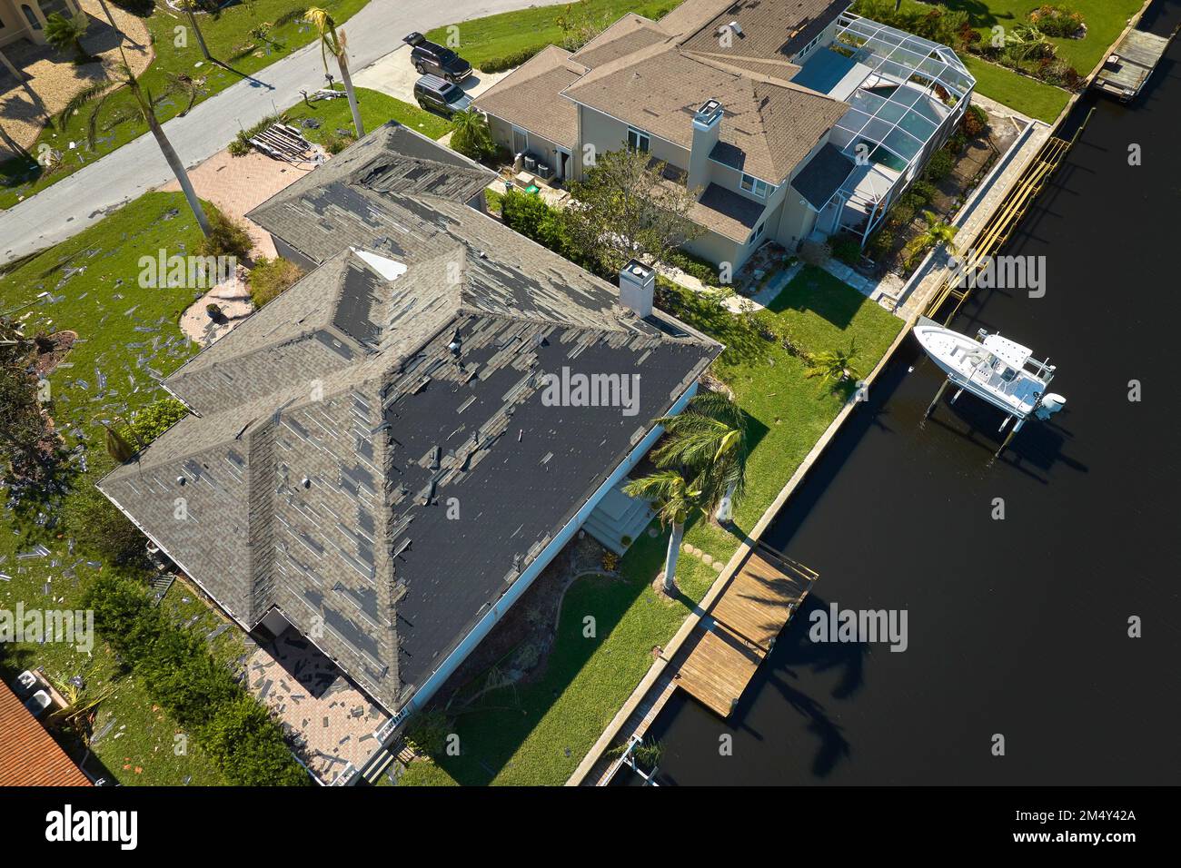 Wind damaged house roof with missing asphalt shingles after hurricane ...