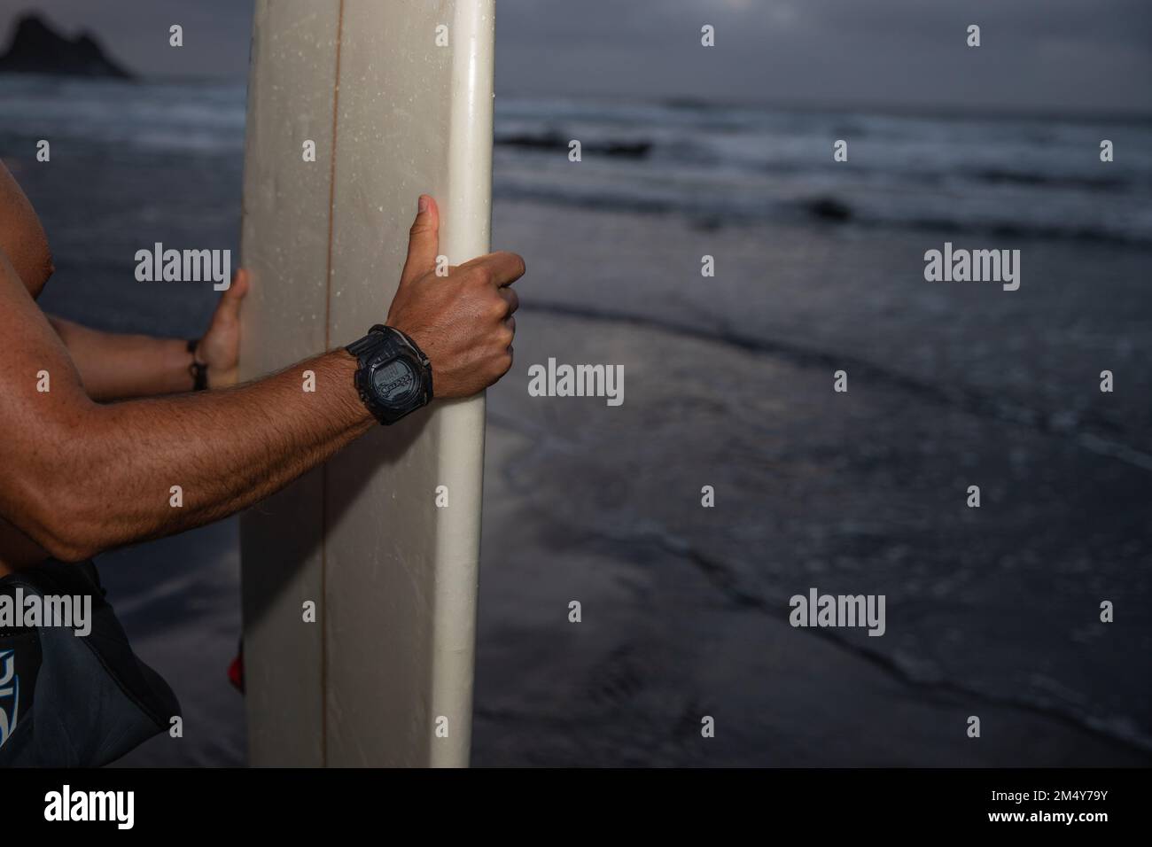 Surfer holds up a surfboard at the beach, photo with copy space on the ...