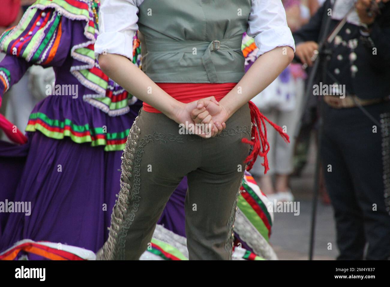 A low-angle shot of a person dancing a Mexican folk dance on the street ...