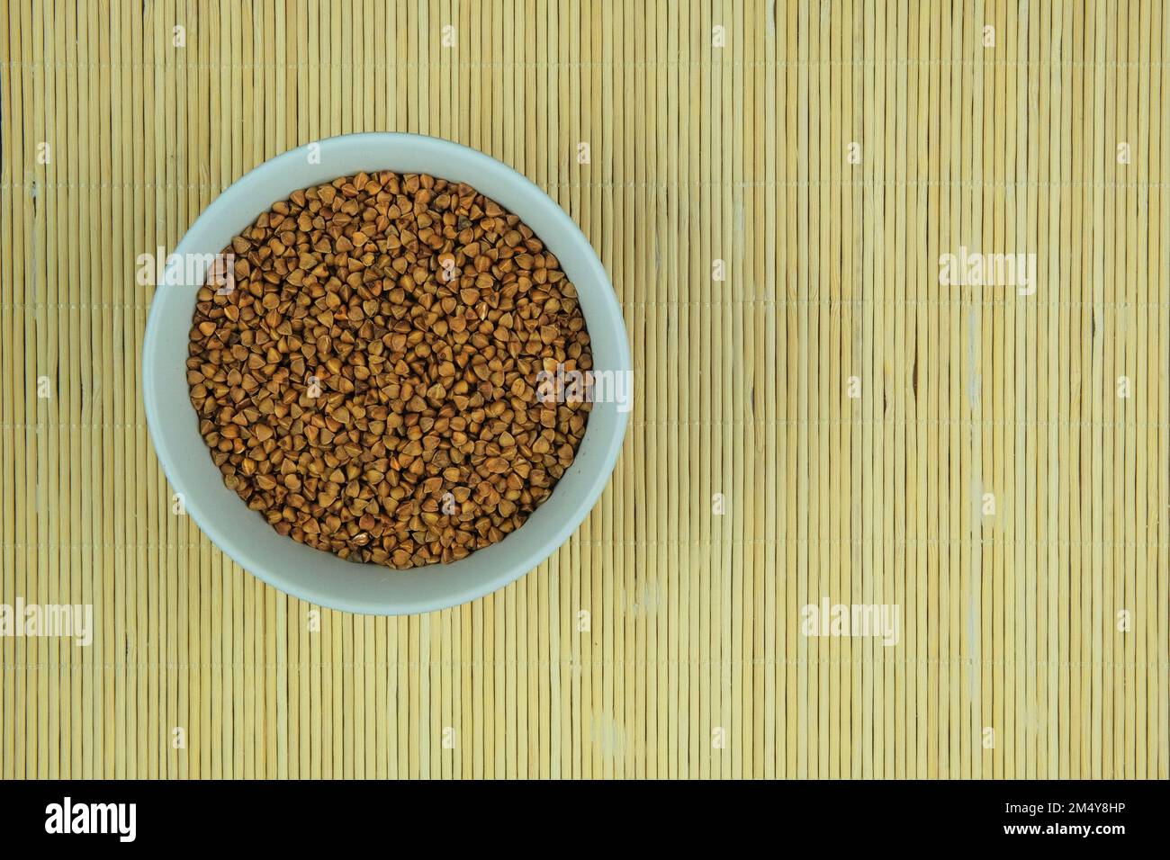 Buckwheat in bowl on a straw background. Vegetarian organic product ...