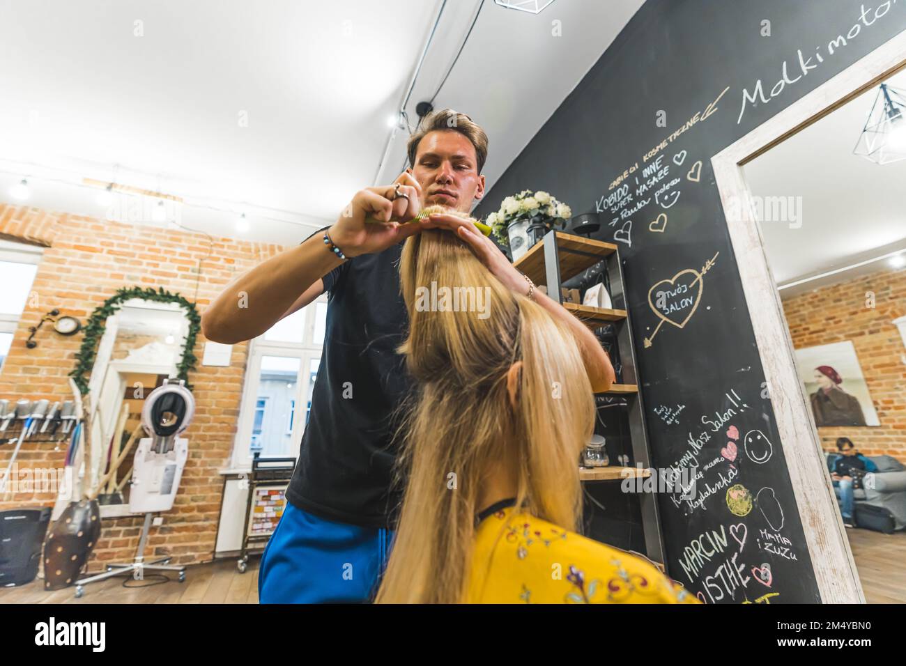 Male hair expert working on new haircut for his blond client. Modern ...