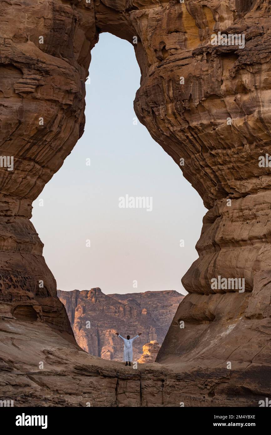 Man standing in a giant hole in the rock, Al Ula, Kingdom of Saudi ...