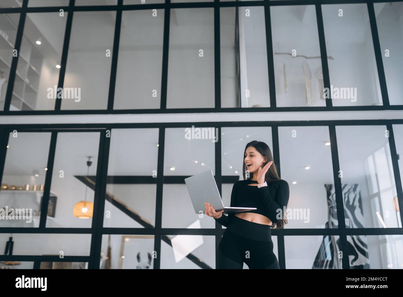 Young woman in a sports suit standing holding a laptop in her hands ...