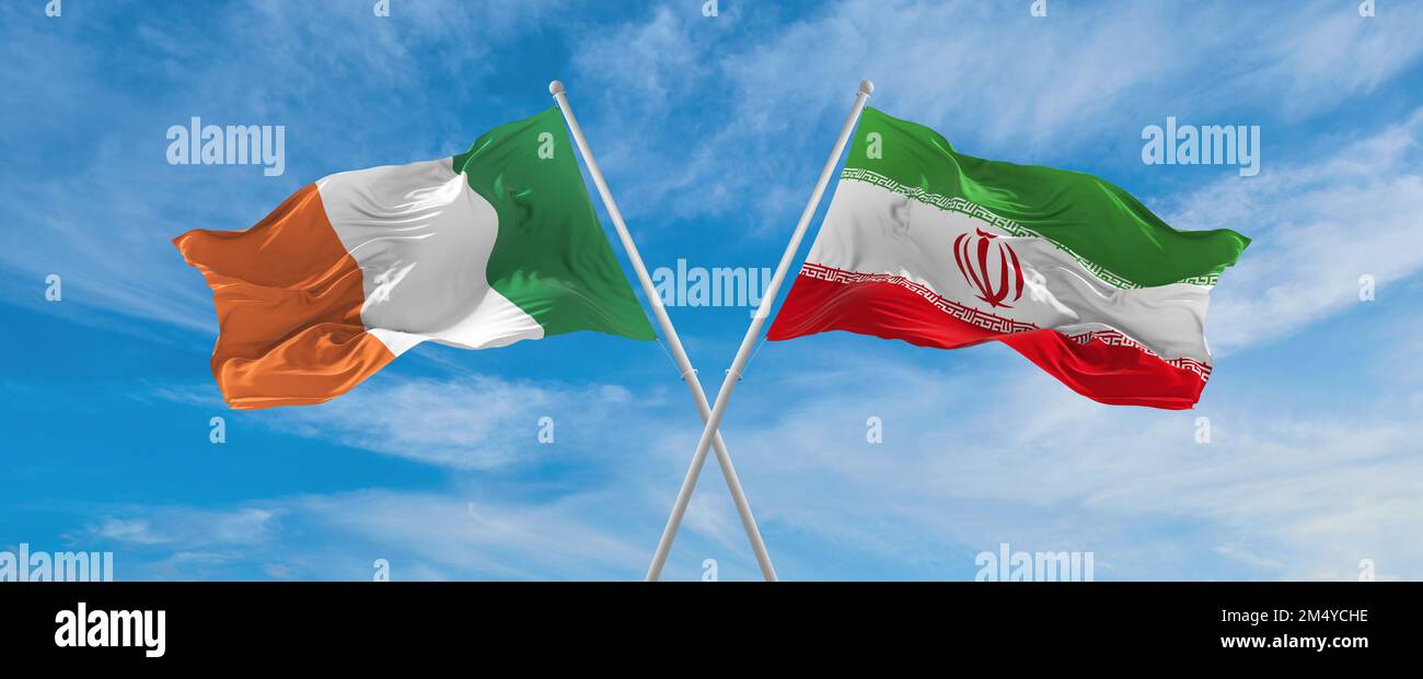 two crossed flags Iran and Ireland waving in wind at cloudy sky ...