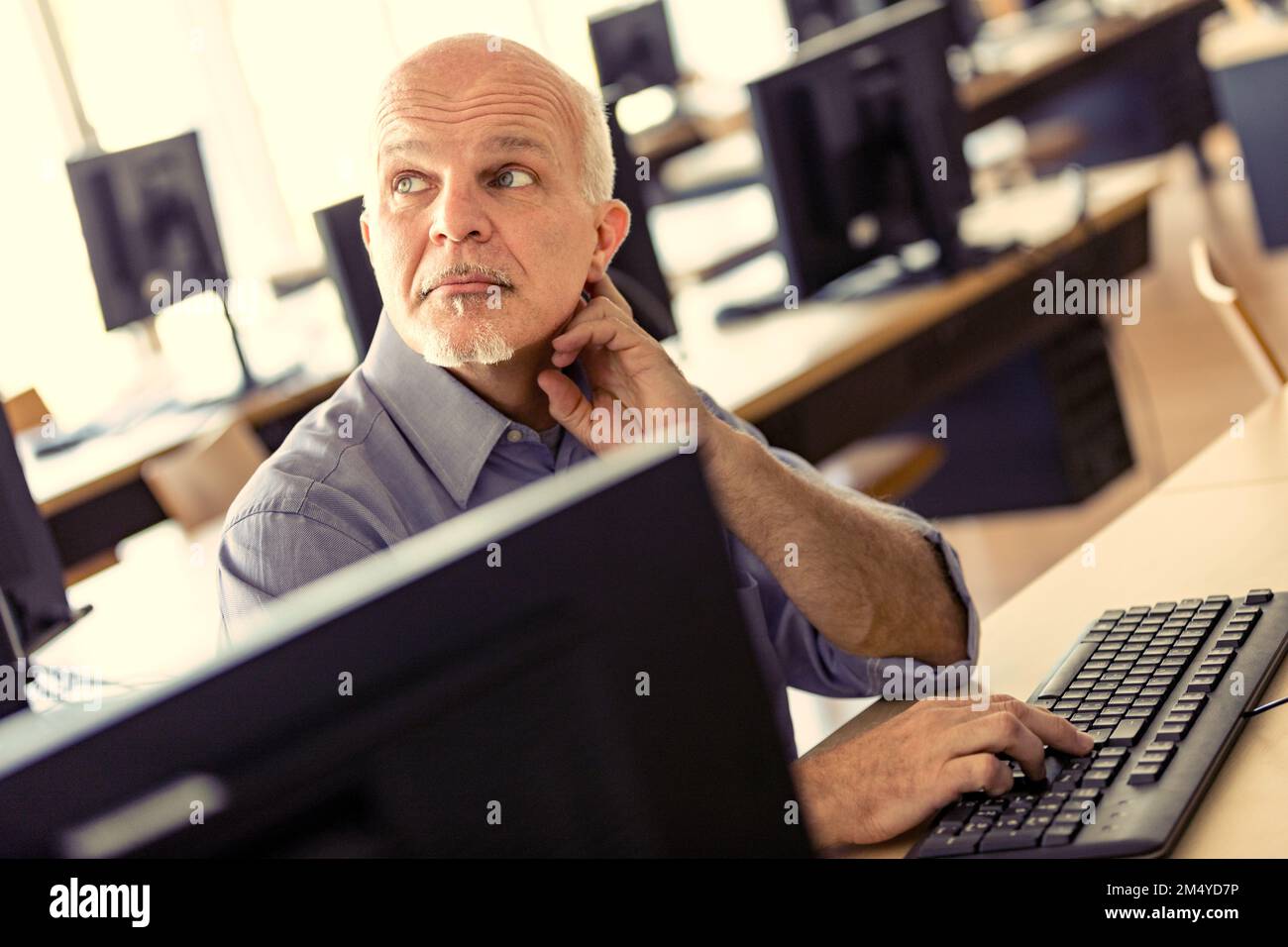 man at the computer listens to a colleague's opinion; he has one hand ...