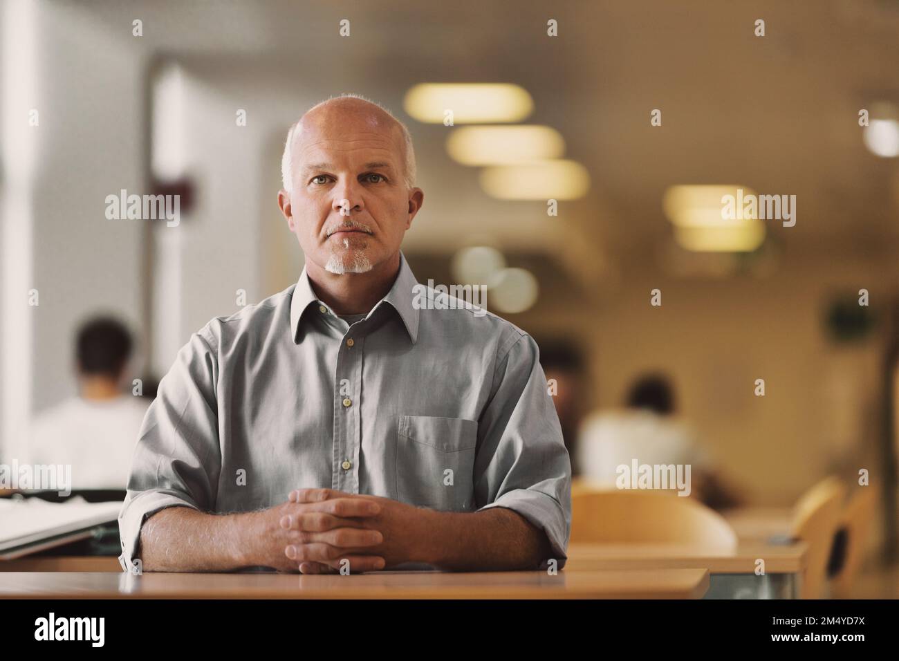 Middle-aged man sitting with intertwined hands among other people out ...
