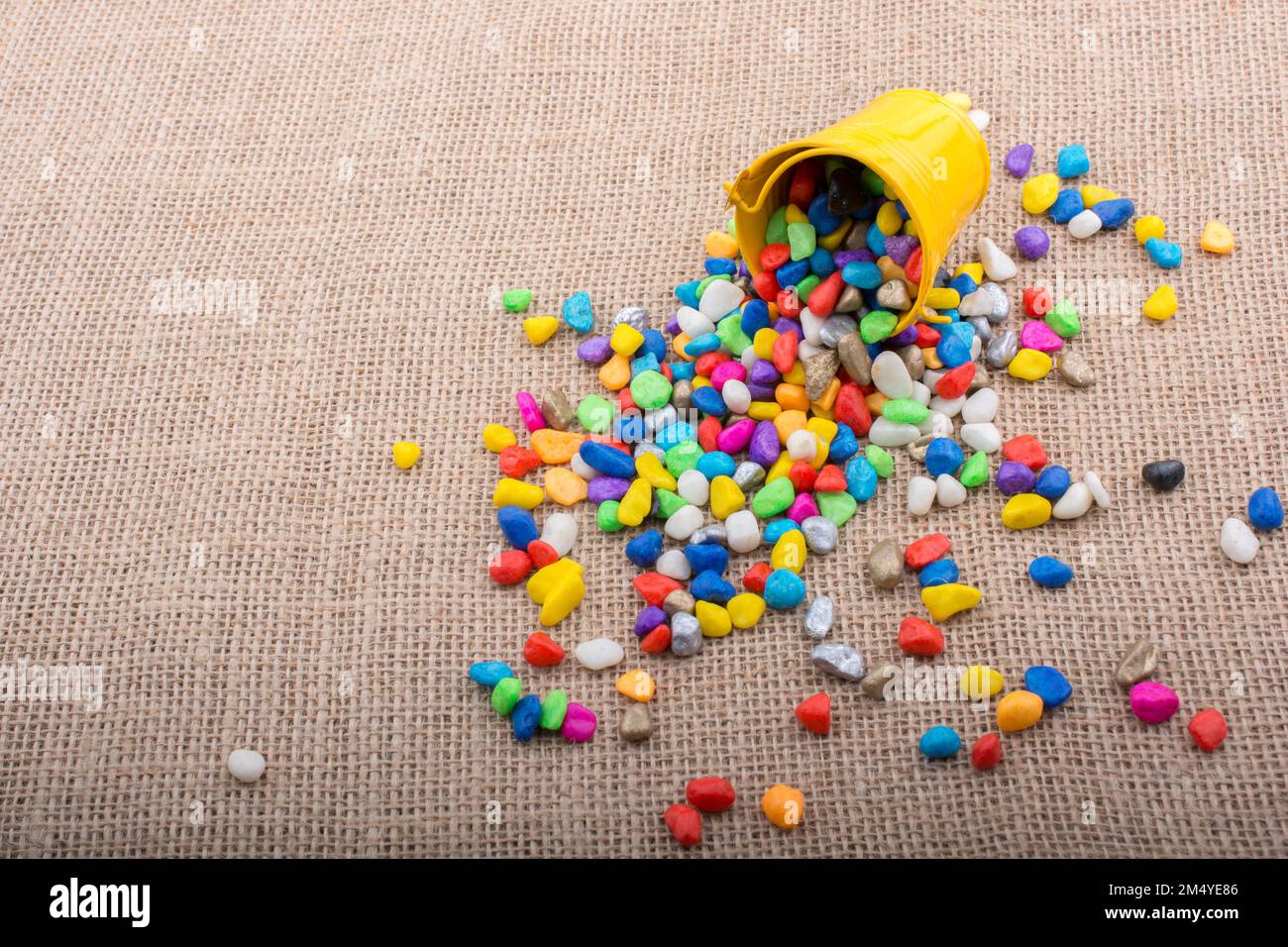 Bucket of colorful pebbles spill on background Stock Photo - Alamy