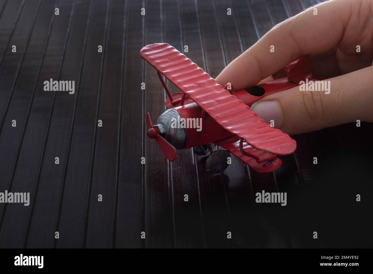 Hand holding a red toy plane on a on wooden texture Stock Photo - Alamy
