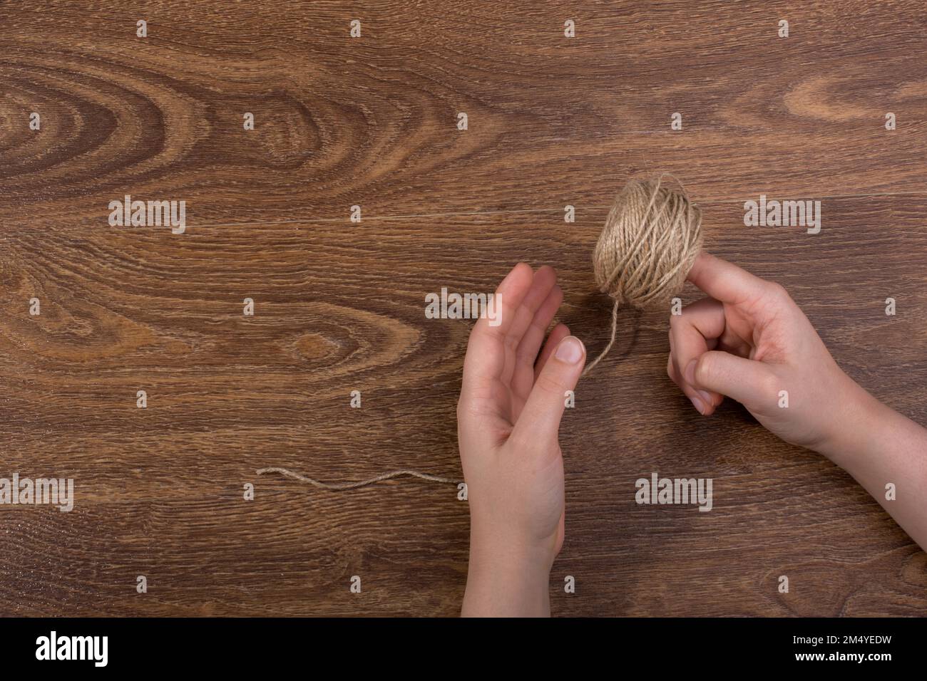 Spool of brown string in hand on brown background Stock Photo - Alamy