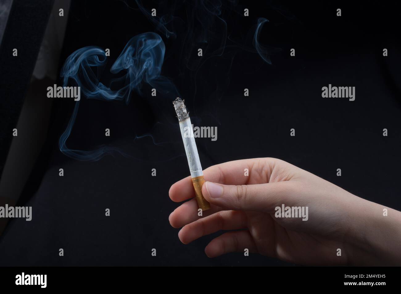 Hand is holding smoking cigarette with smoke around Stock Photo - Alamy
