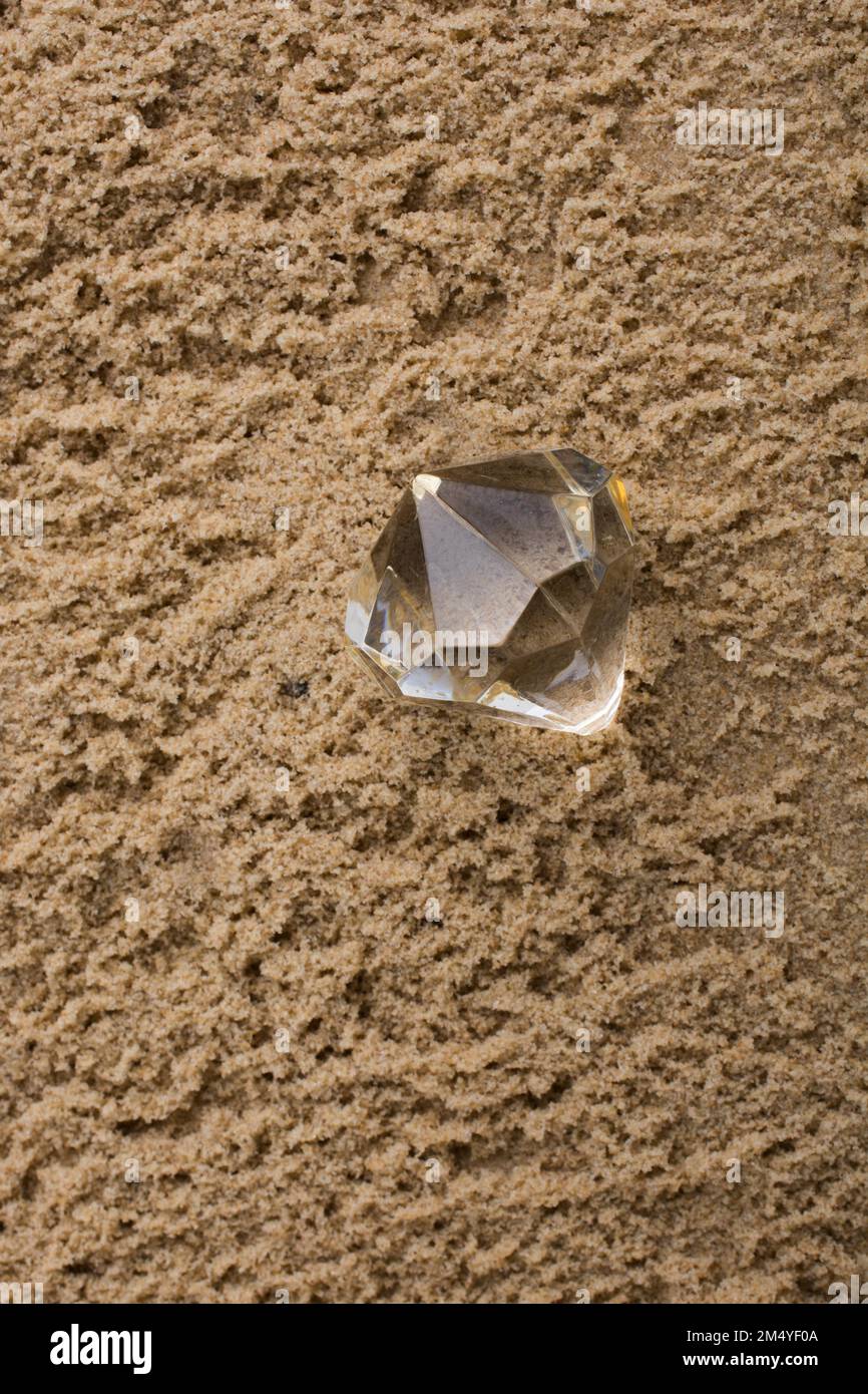 A transparent diamond on a sand background on display Stock Photo - Alamy