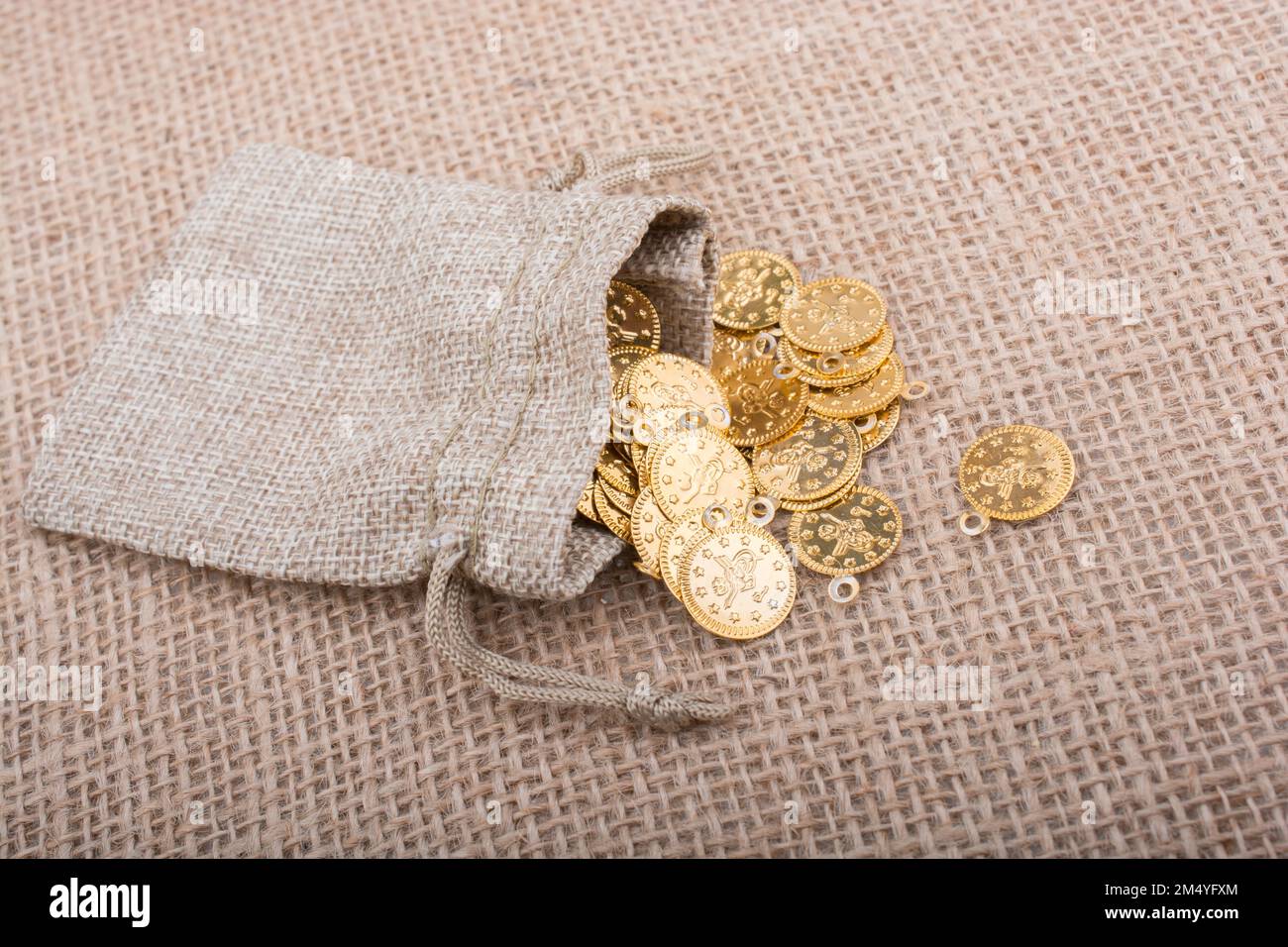 Fake gold coins out of a little sack on canvas Stock Photo - Alamy