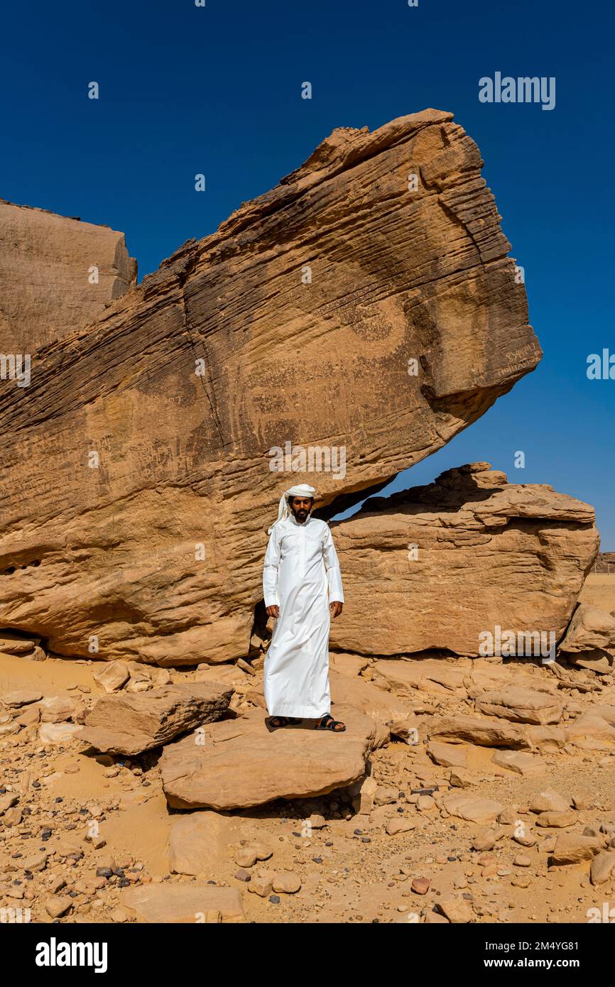 Man pointing at rock carvings, Unesco site Bir Hima Rock Petroglyphs ...