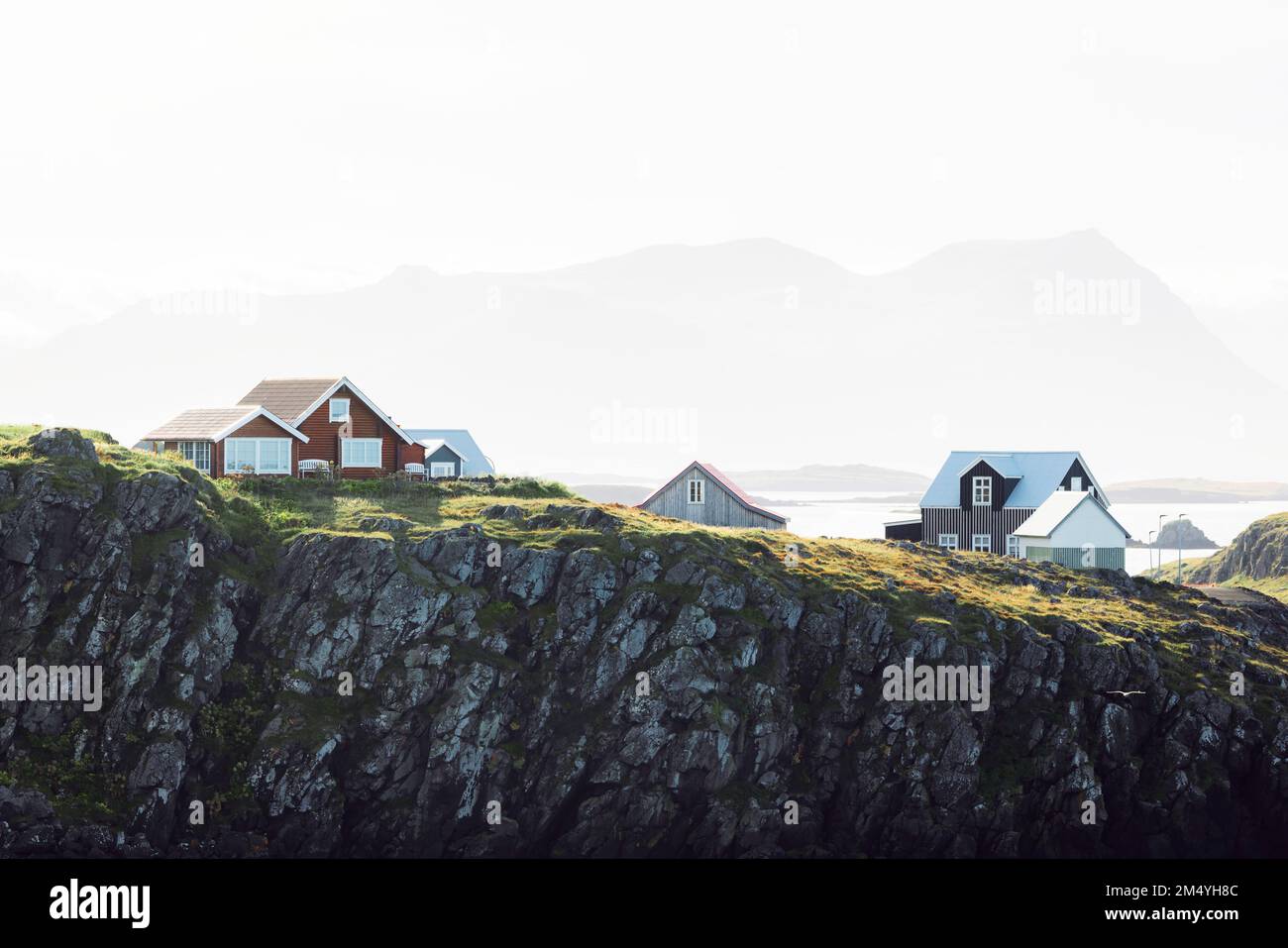 Red typical Icelandic wooden houses on the edge of a cliff near sea ...
