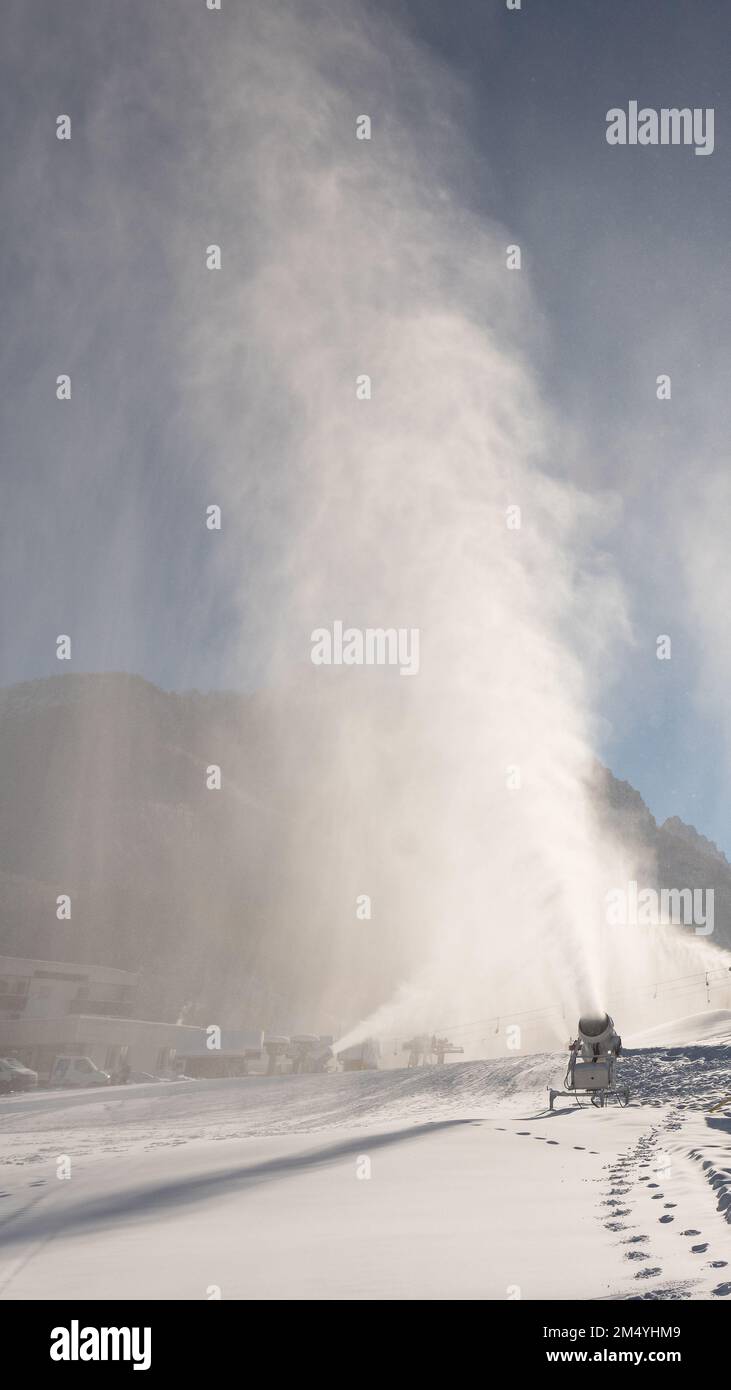 Snowmaking machine snow cannon or gun in action on a cold sunny winter ...