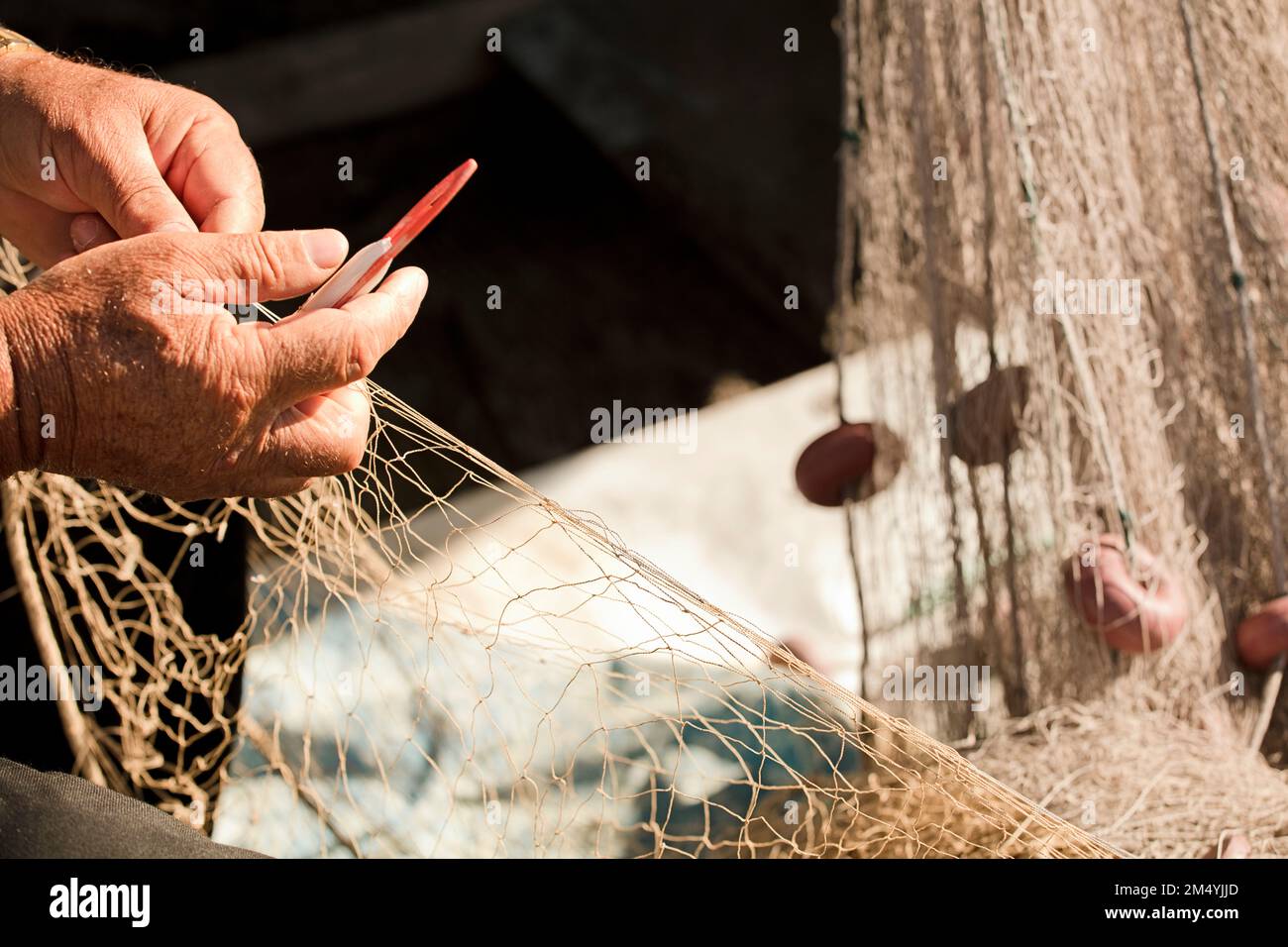 fishing net in the hands of fisherman, he weaves and repairs by sewing ...