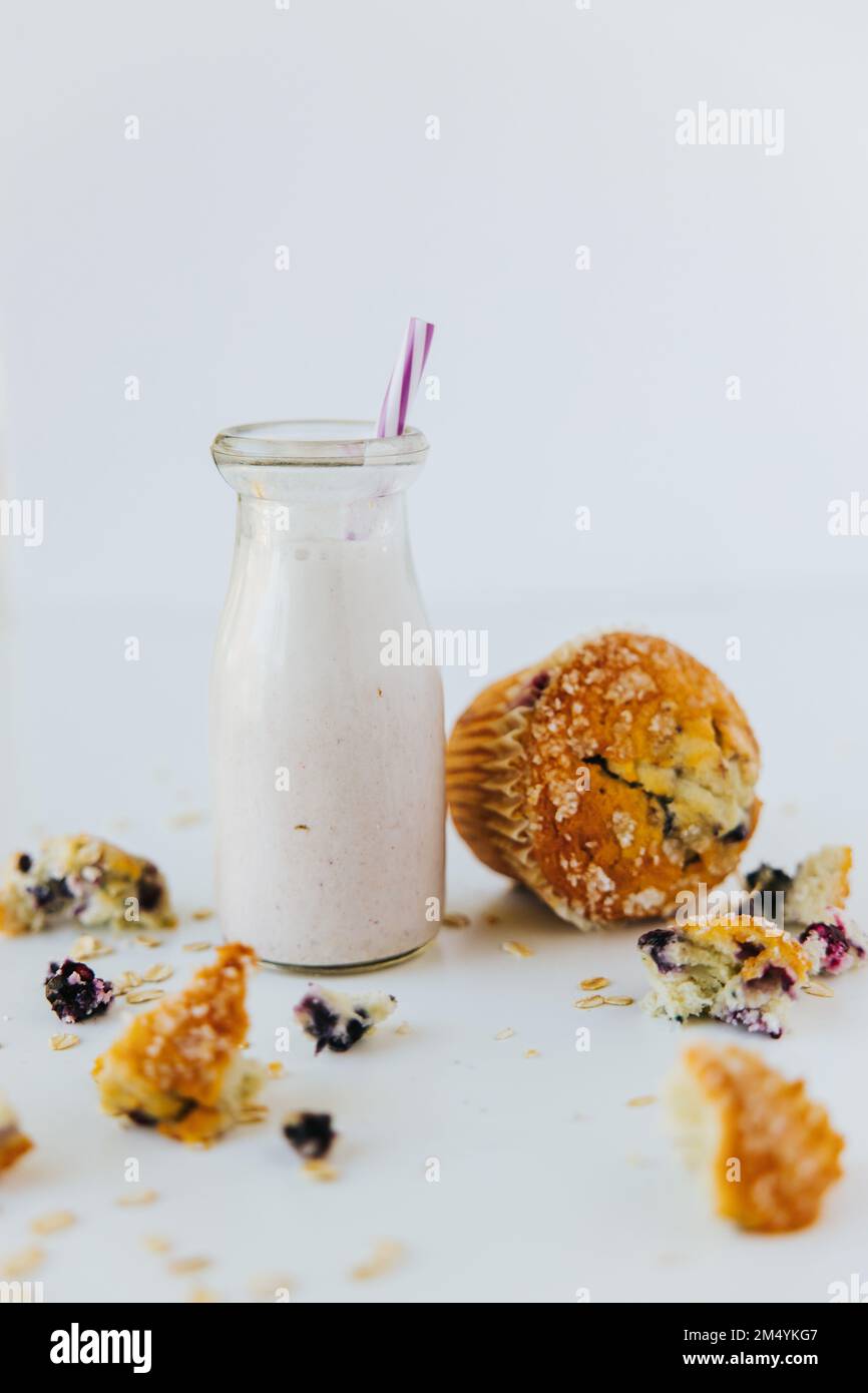 A vertical closeup shot of a glass of a protein shake with a muffin on ...