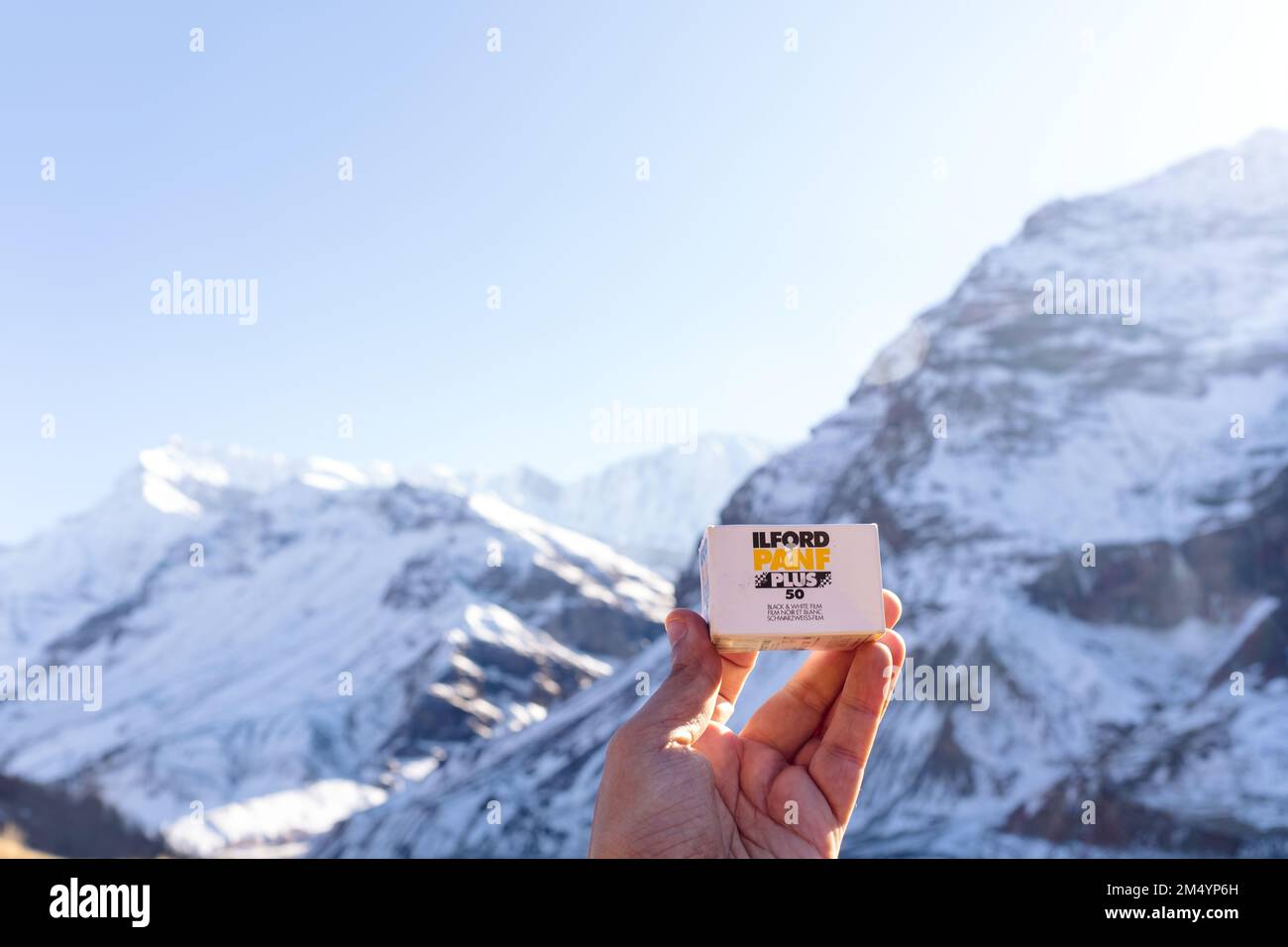 A closeup of a person hand holding Ilford camera roll against huge ...