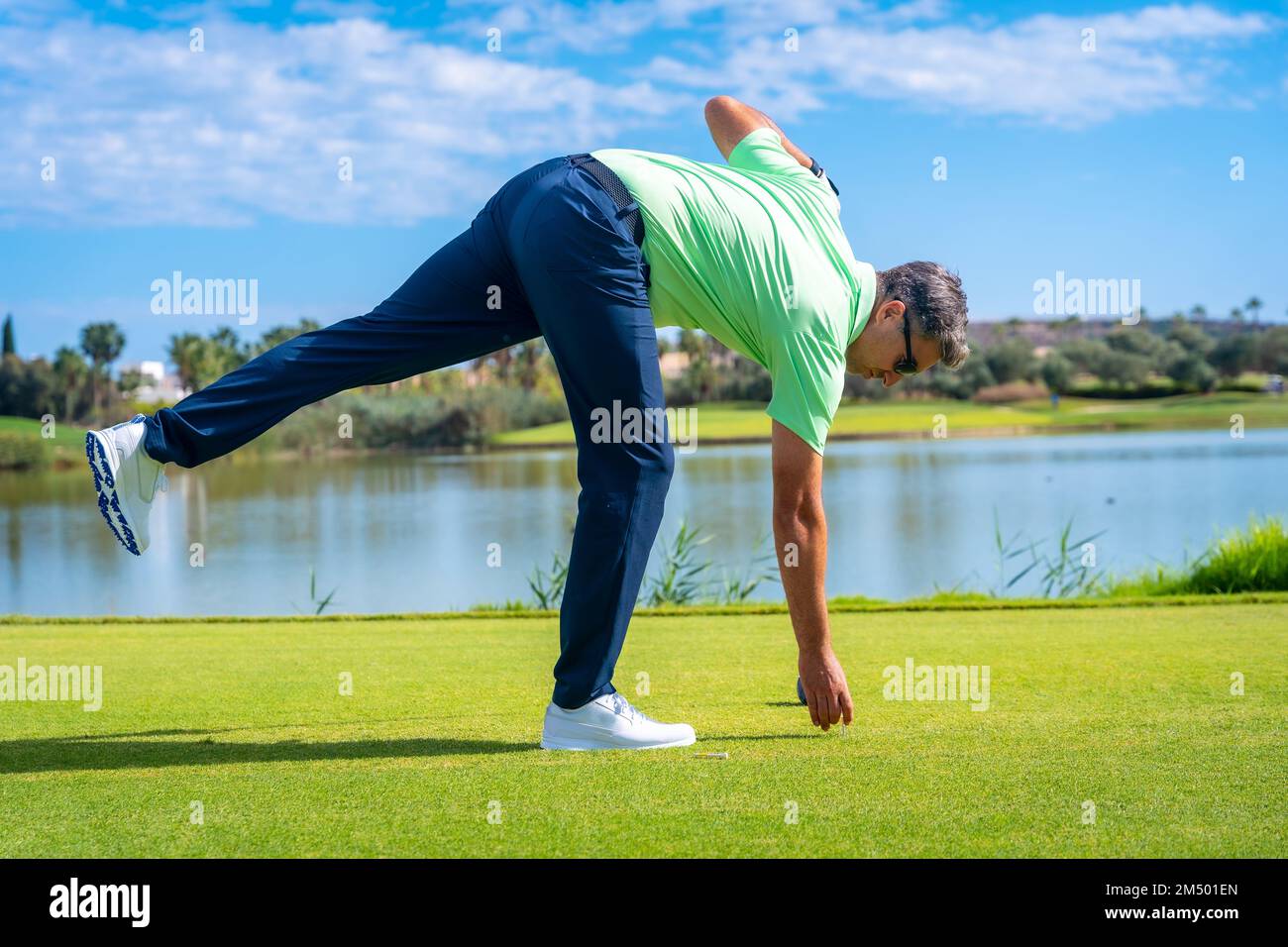 A scenic view of a Caucasian man playing a golf match on a bright sunny ...