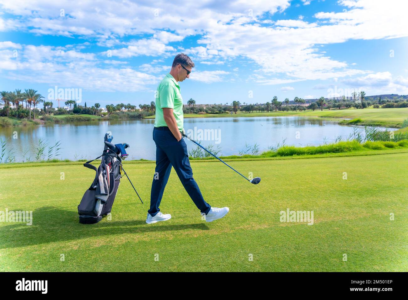 A scenic view of a Caucasian man playing a golf match on a bright sunny ...