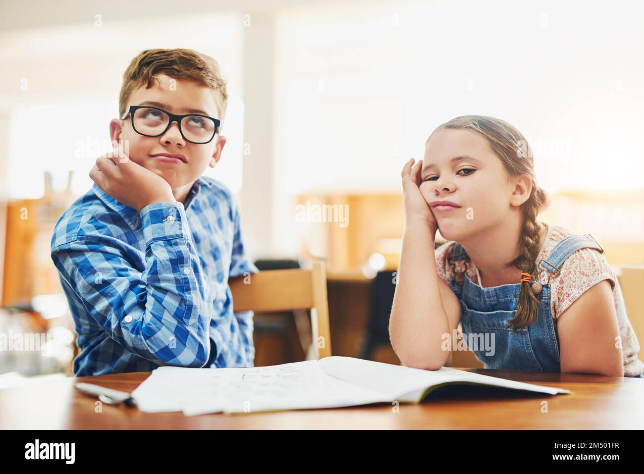 They look bored. two young children working together at school while ...