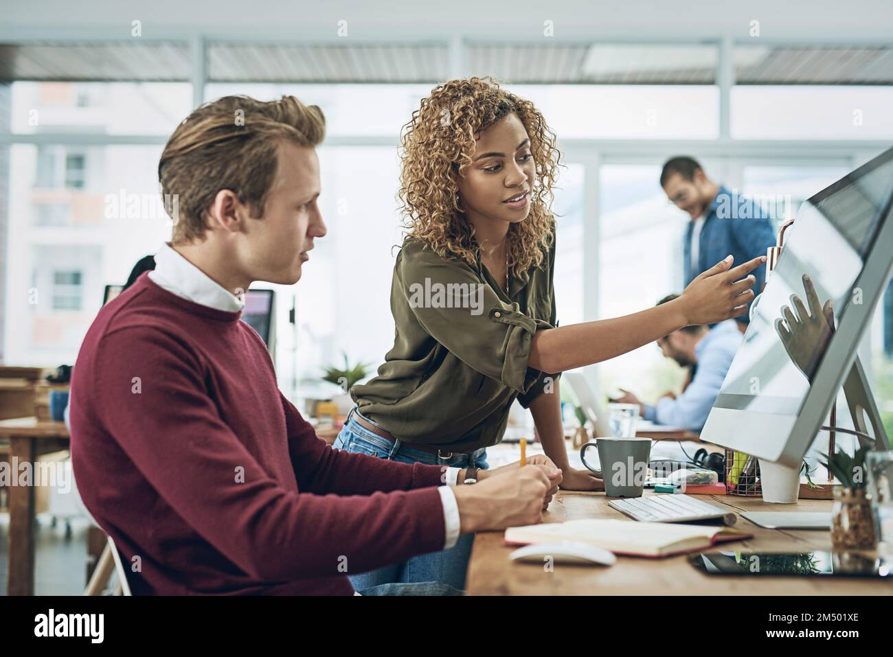 Shared resources bring shared success. two young colleagues using a ...