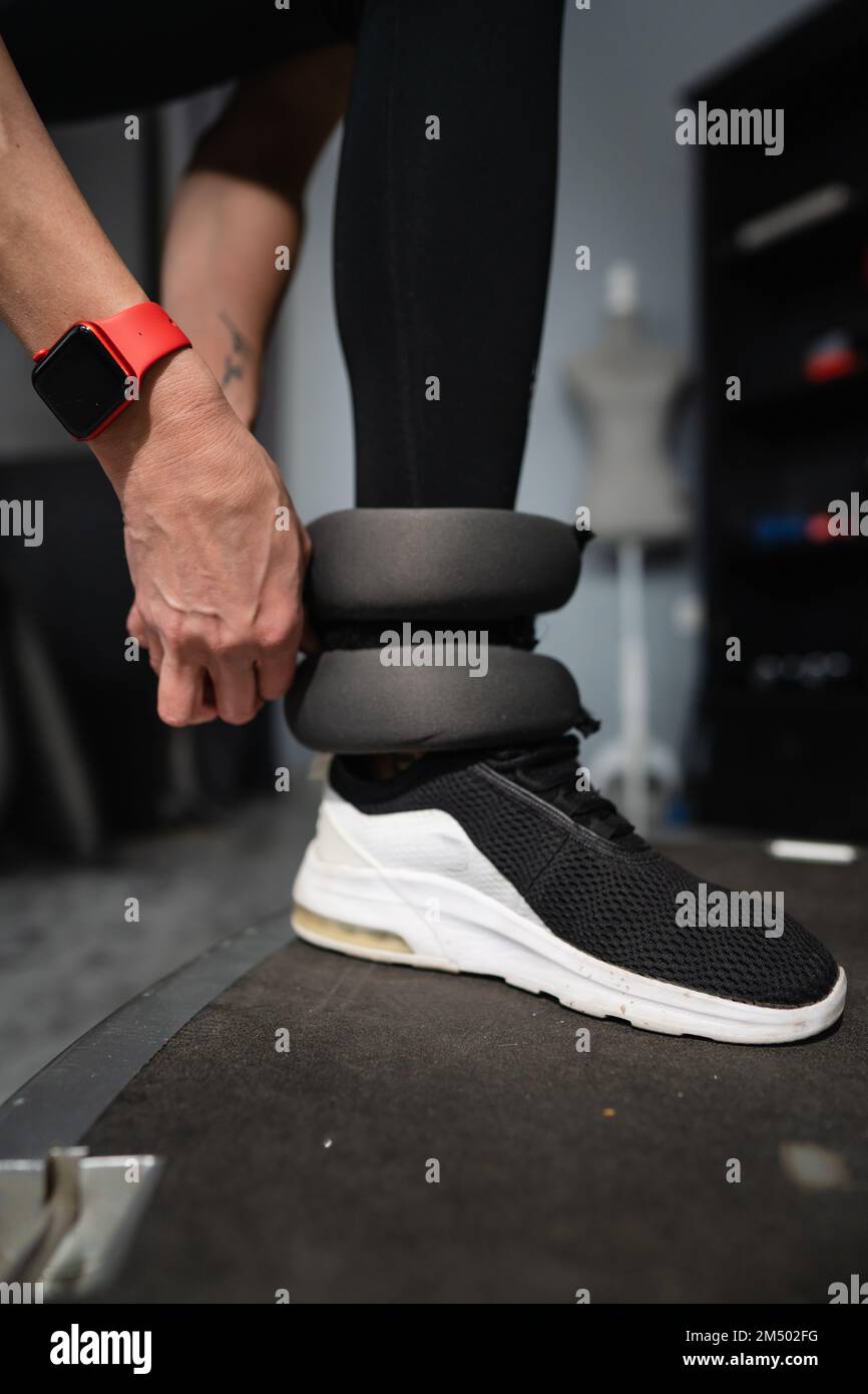 Close up on foot of unknown caucasian woman putting ankle weight on the ...