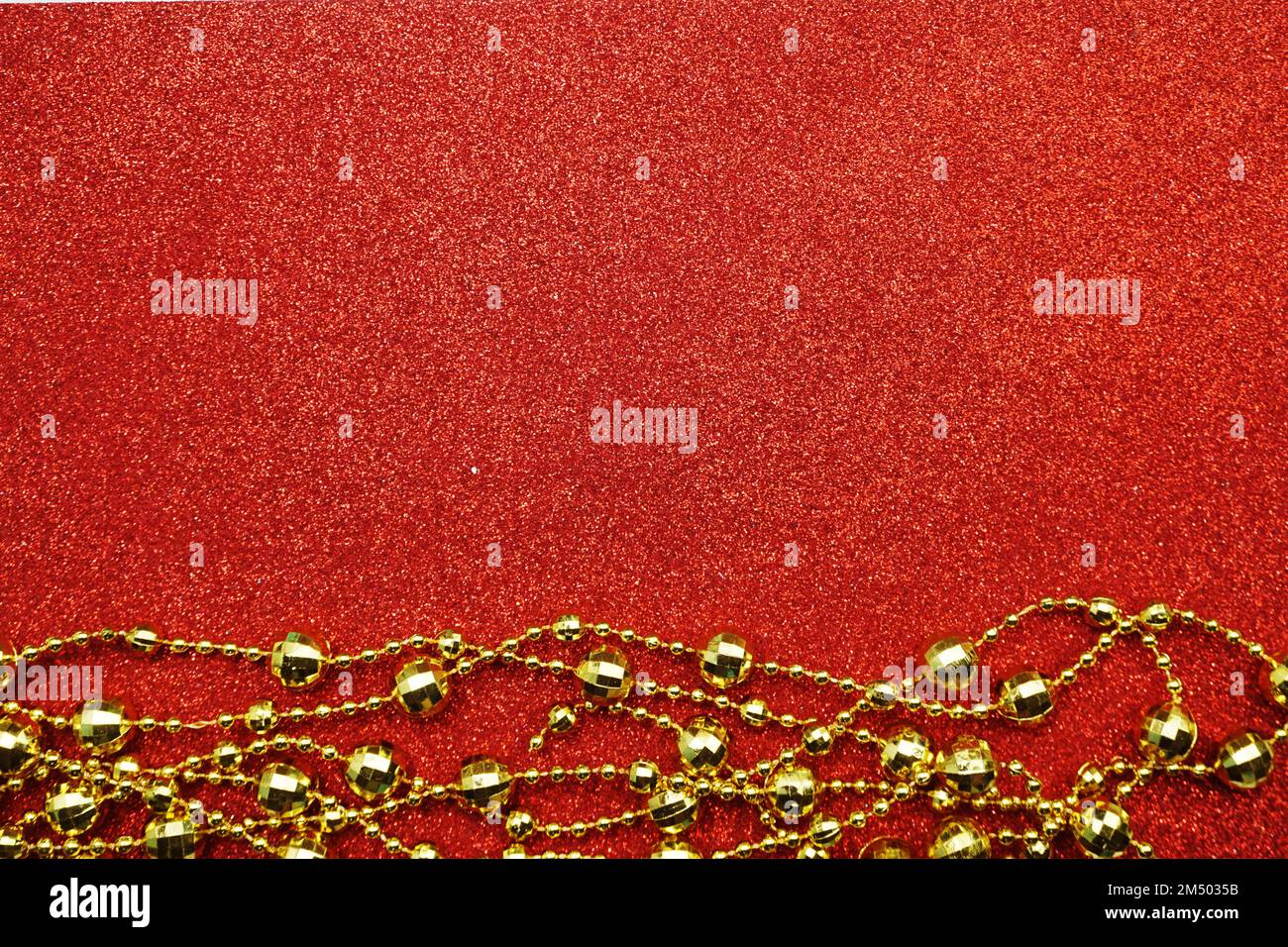 Christmas garlands with gold decorations with space copy on red glitter ...