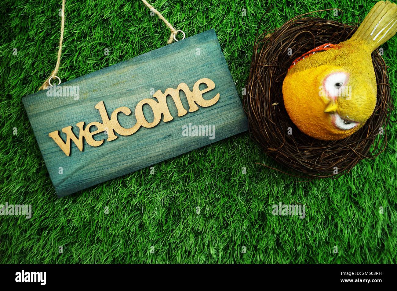 colorful bird statue with nest and Welcome sign on artificial green ...