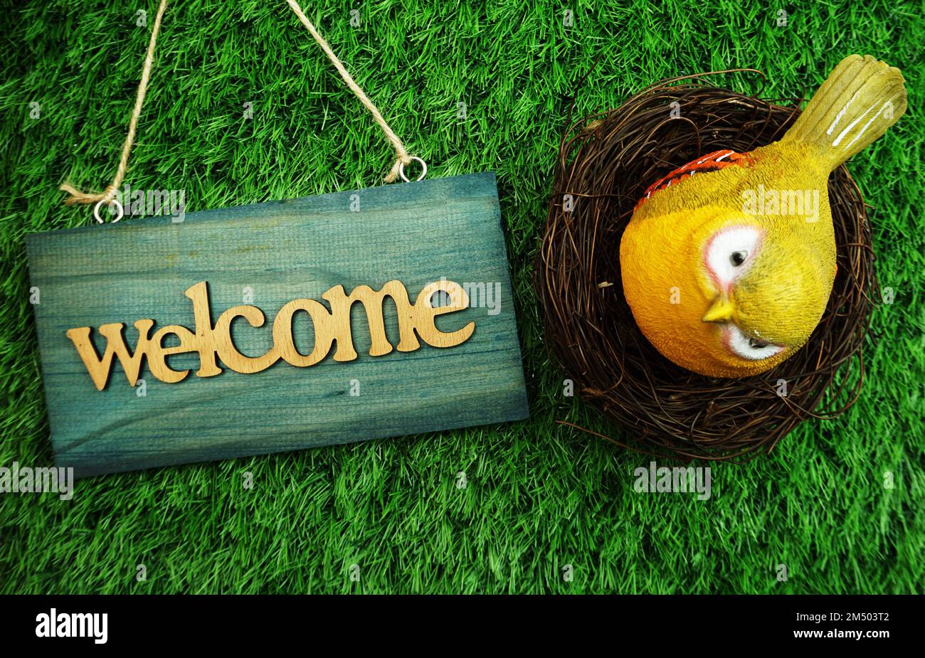 colorful bird statue with nest and Welcome sign on artificial green ...