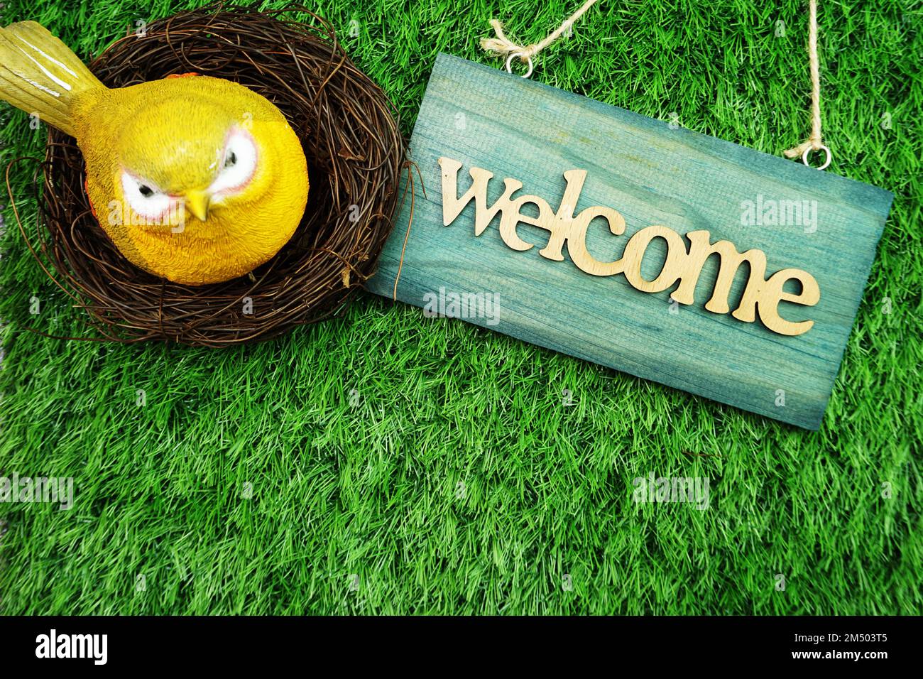 colorful bird statue with nest and Welcome sign on artificial green ...