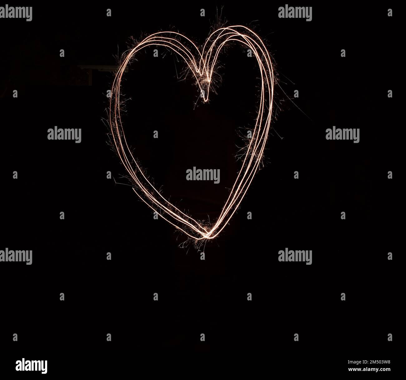 Love and light in the darkness. a hart being drawn with a sparkler ...