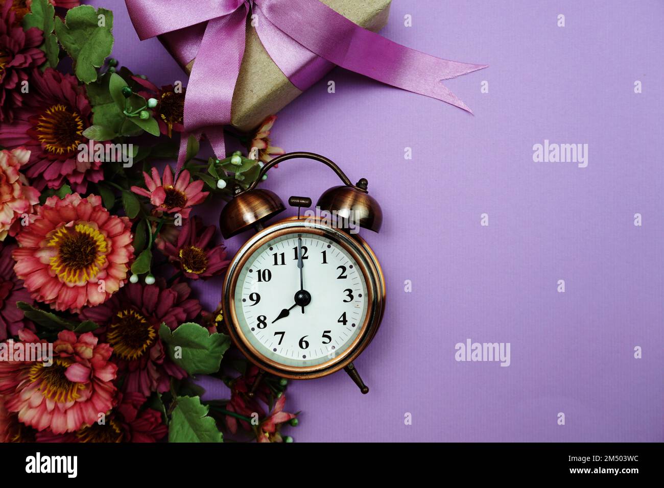 Gift box with flower and alarm clock on purple background Stock Photo ...
