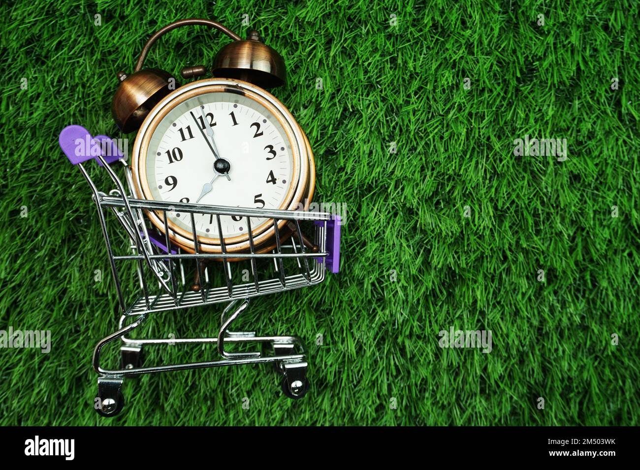 Alarm clock and Mini trolley cart with space copy on green grass ...