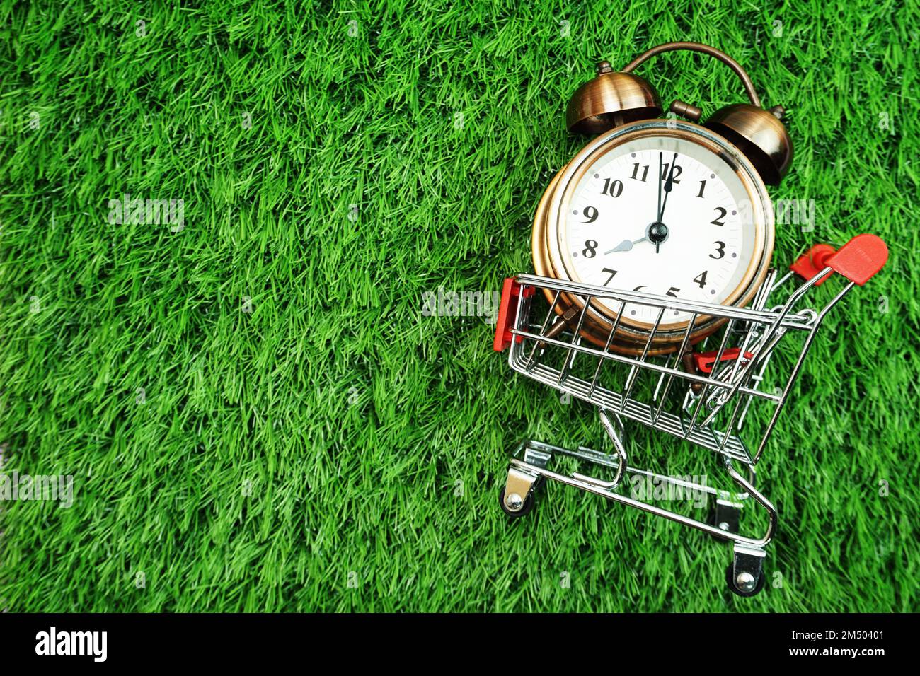 Alarm clock and Mini trolley cart with space copy on green grass ...