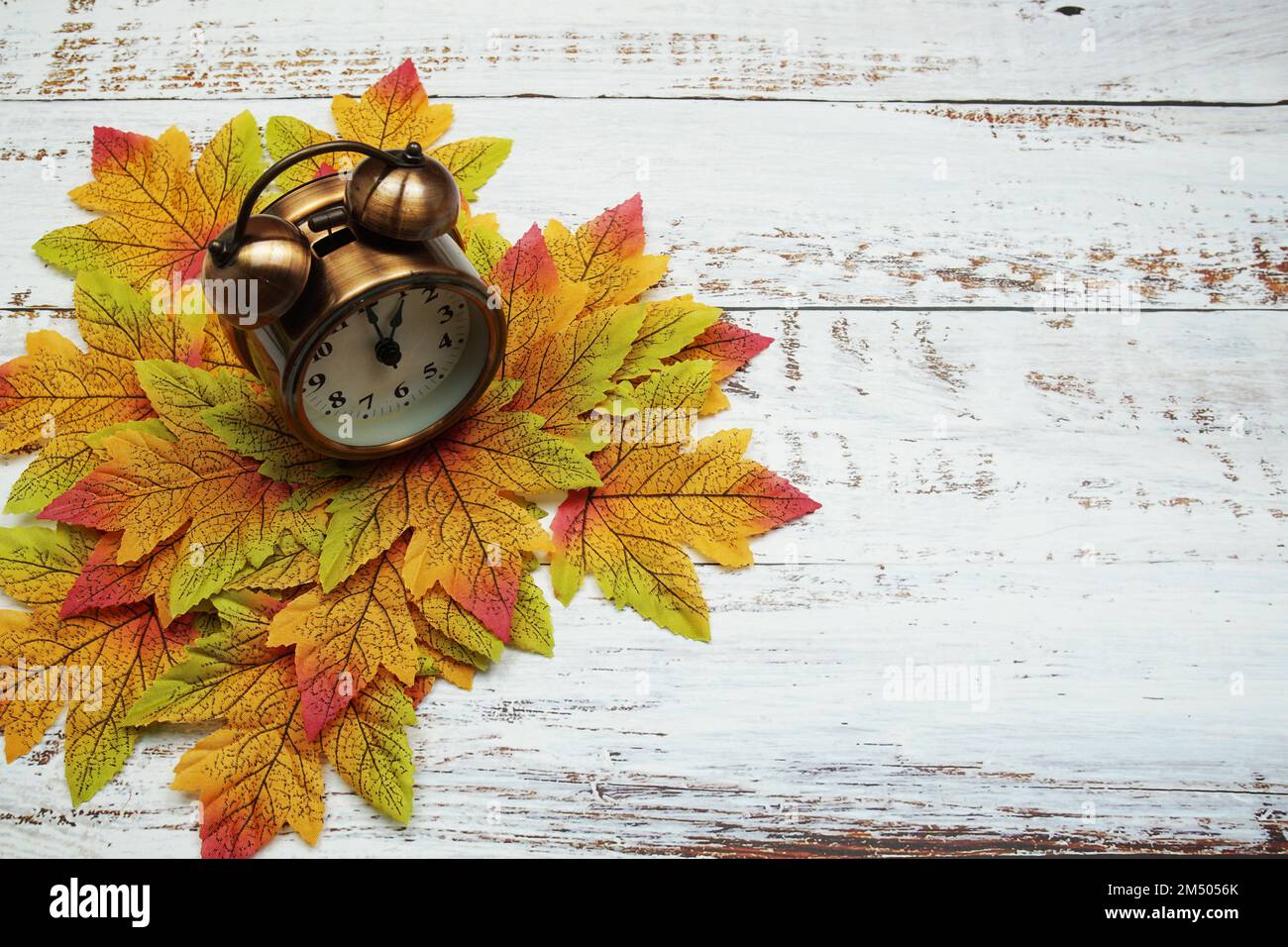 Alarm clock with maple leaves on wooden background Stock Photo - Alamy