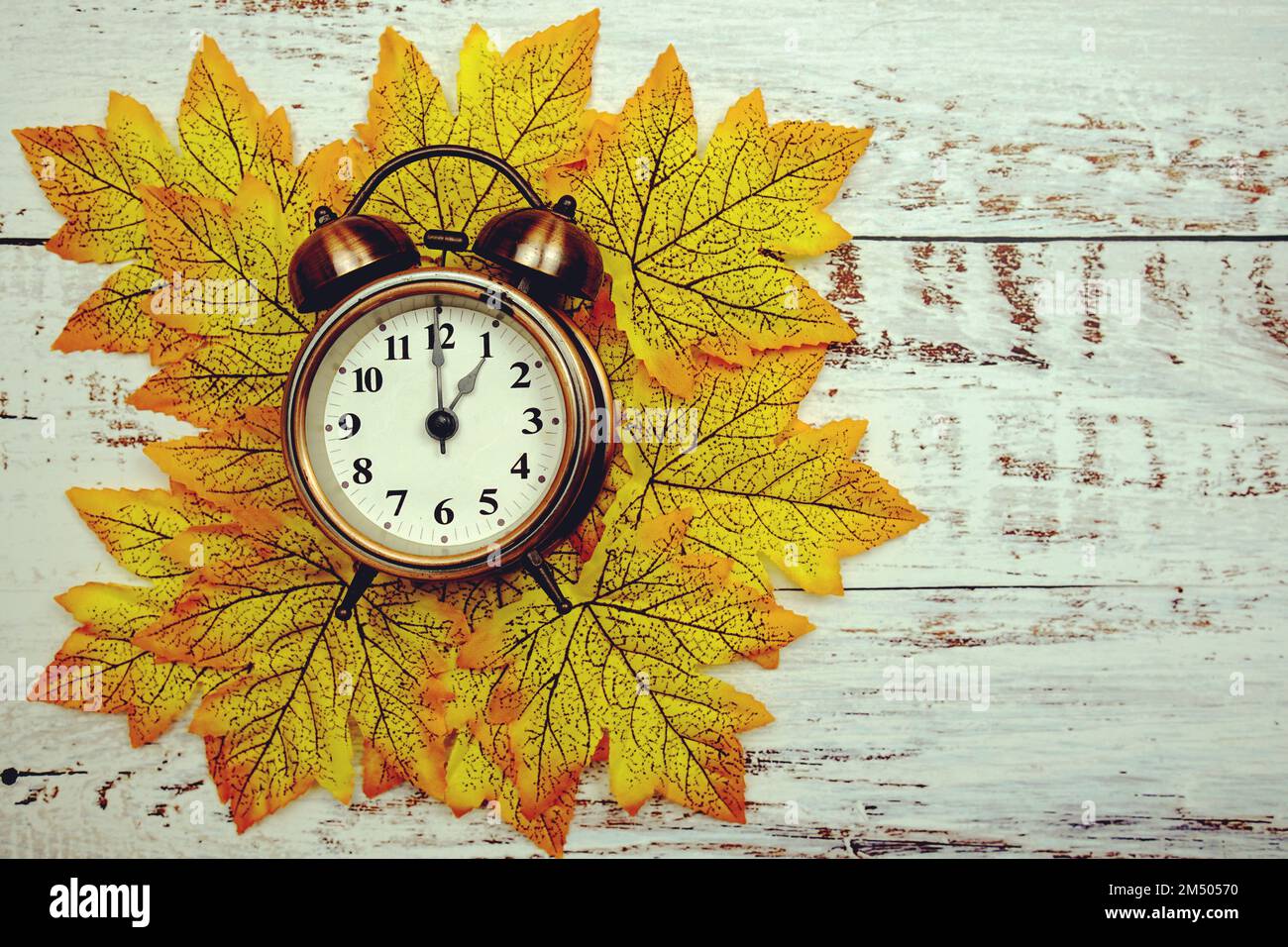 Alarm clock with maple leaves on wooden background Stock Photo - Alamy