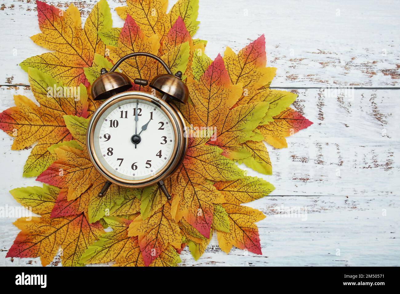 Alarm clock with maple leaves on wooden background Stock Photo - Alamy