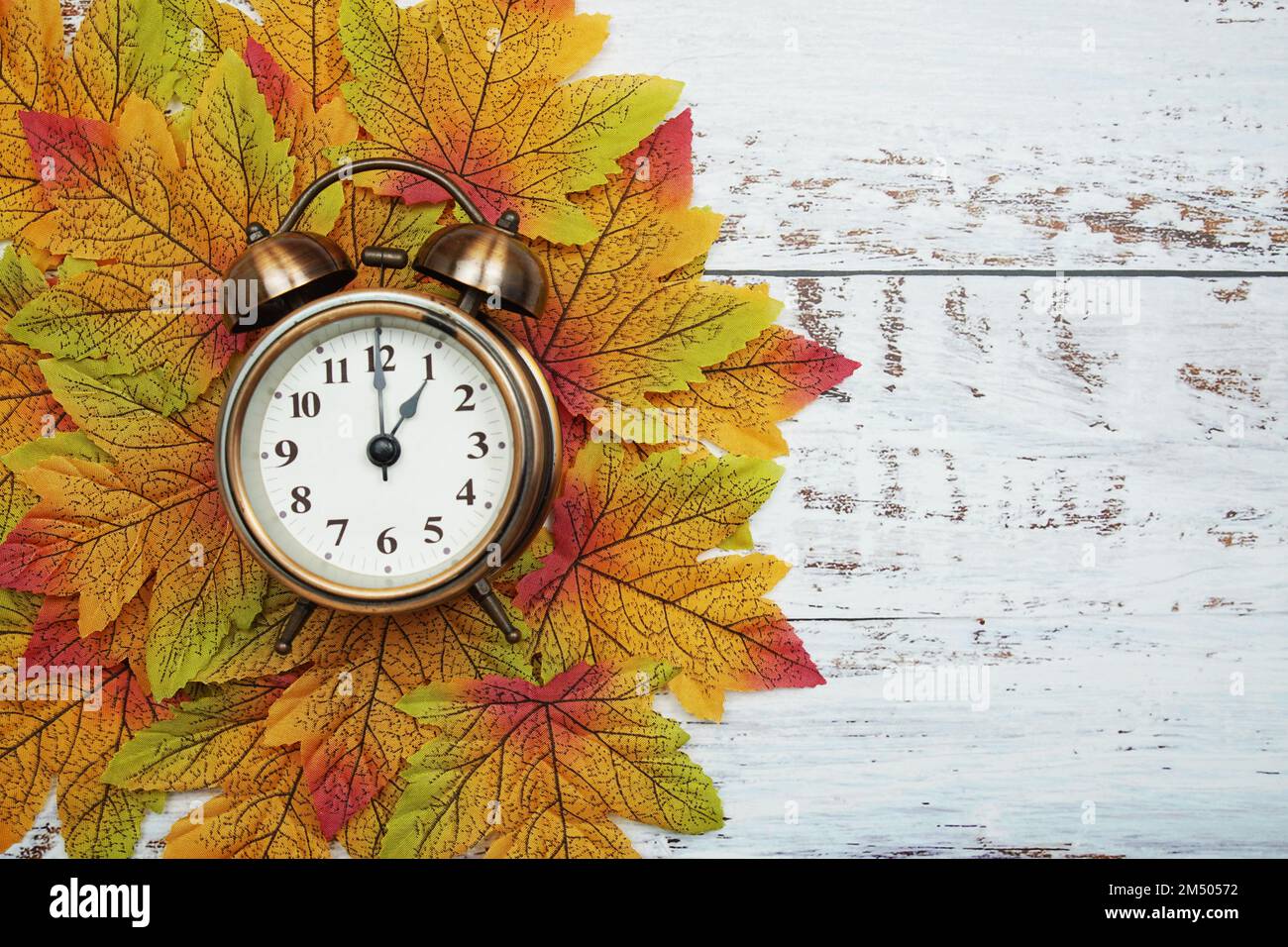 Alarm clock with maple leaves on wooden background Stock Photo - Alamy