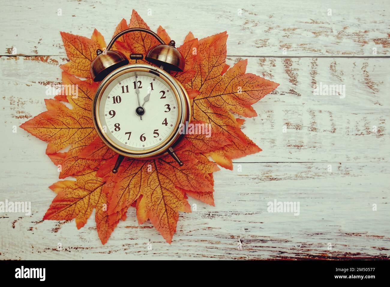 Alarm clock with maple leaves on wooden background Stock Photo - Alamy
