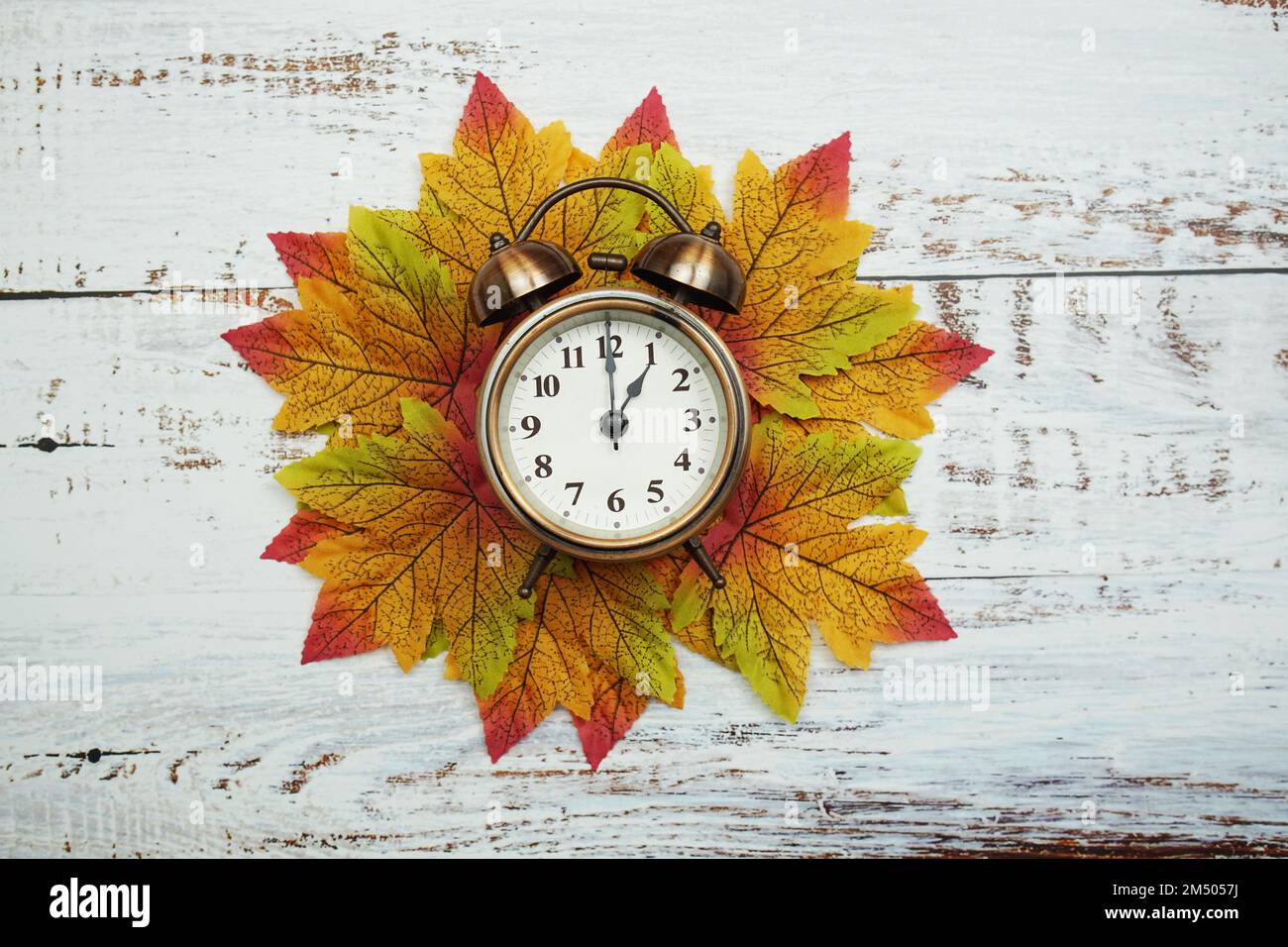Alarm clock with maple leaves on wooden background Stock Photo - Alamy